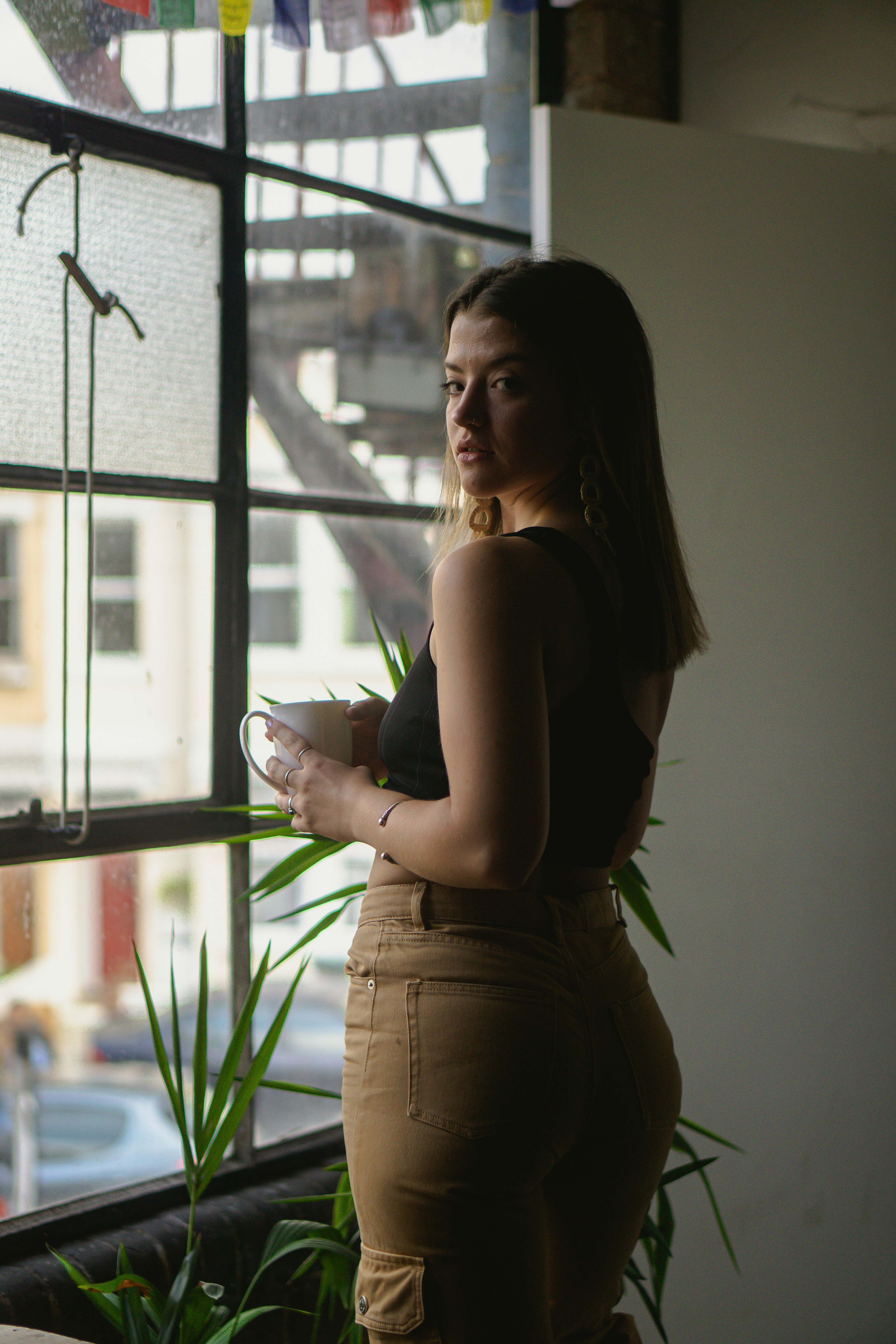 woman in black tank top and brown pants holding clear drinking glass