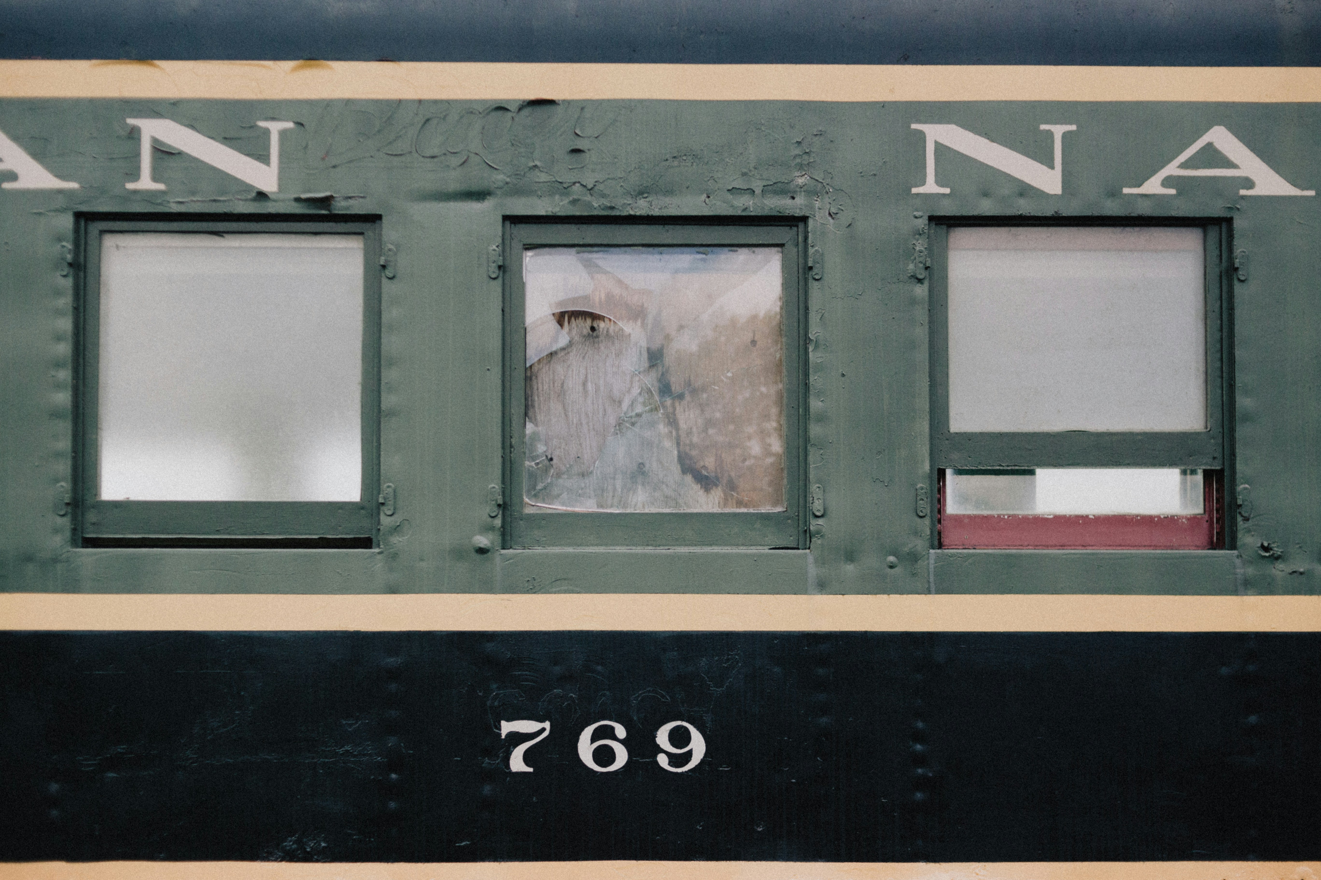 Weathered train car windows revealing a faded mural, hinting at forgotten journeys. The number 769 is prominently displayed beneath the windows.