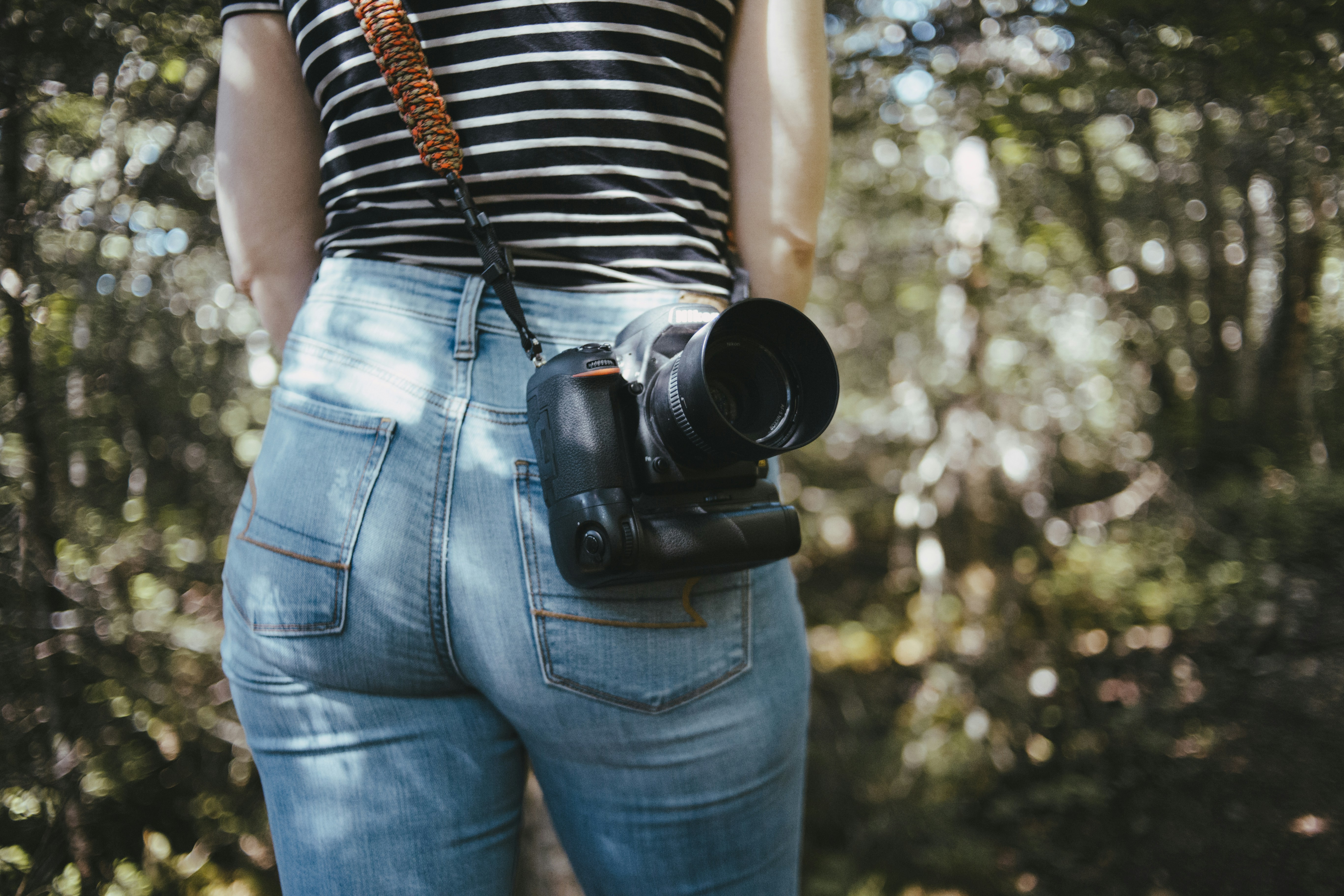 Back-View Photographer in the Forest with a Camera Slung at the Hip