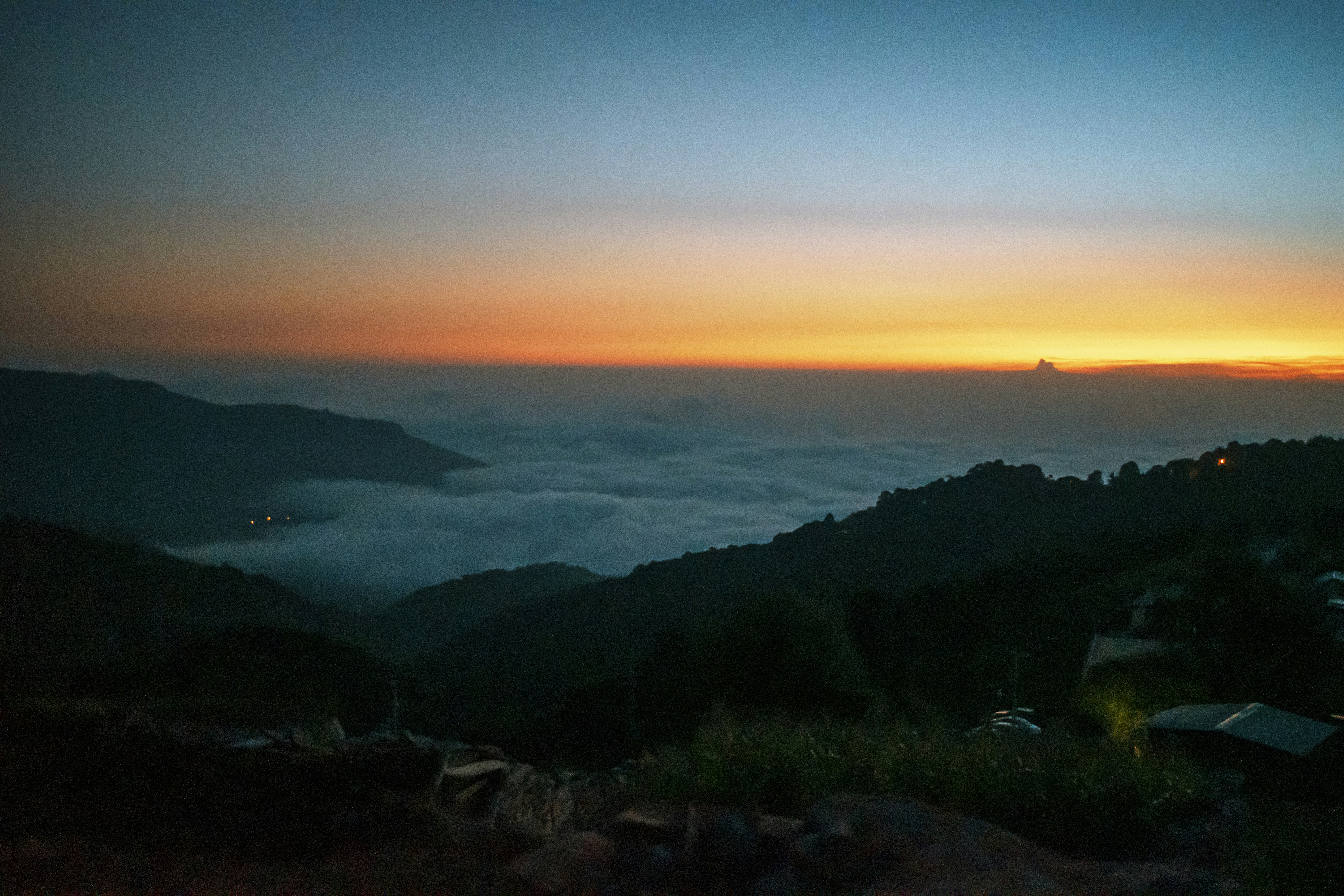 Sunrise illuminates a mist-covered valley between silhouetted hills with vibrant hues.