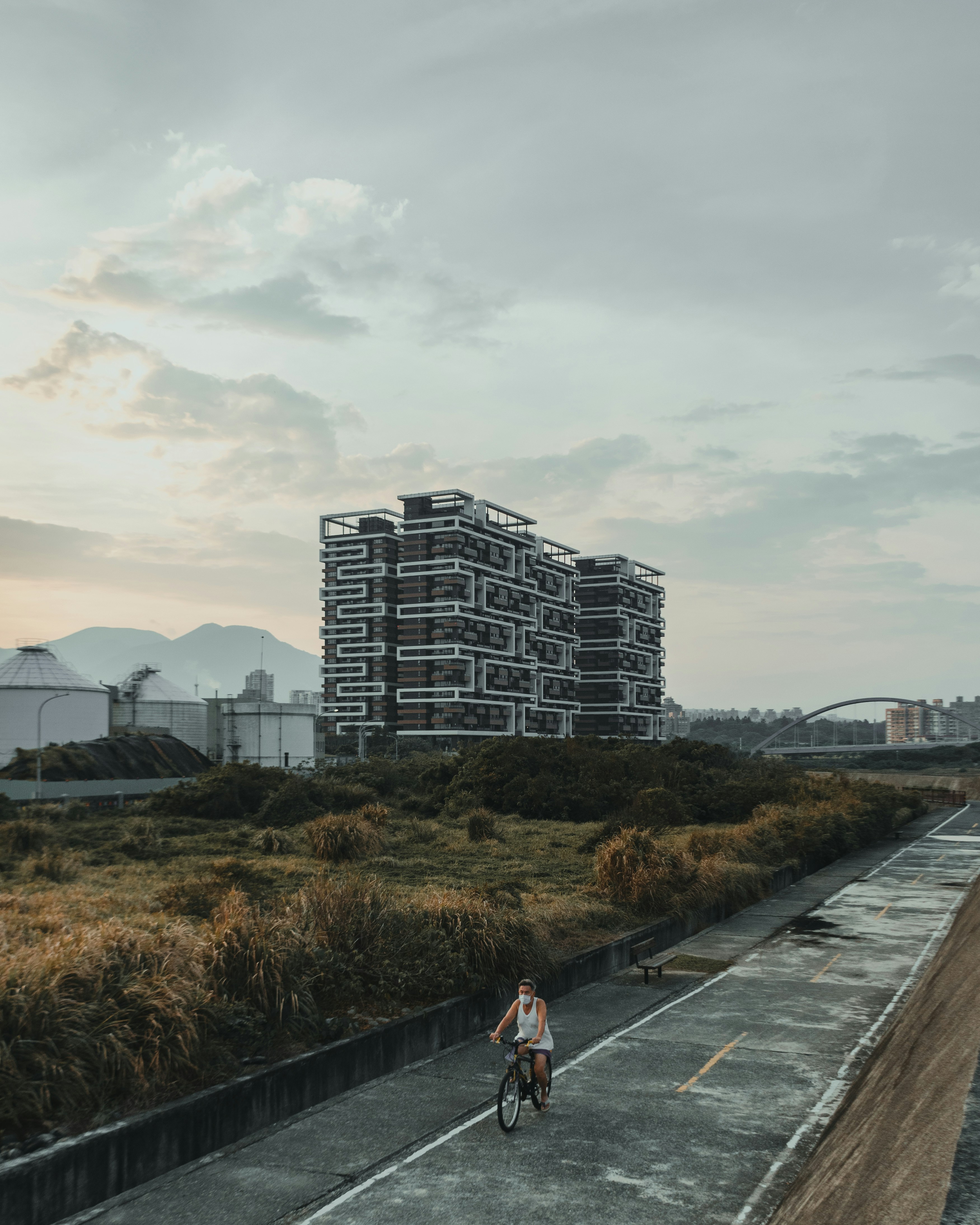 Urban ascent: cyclist on a sunlit transit path with modern stacked-building silhouettes