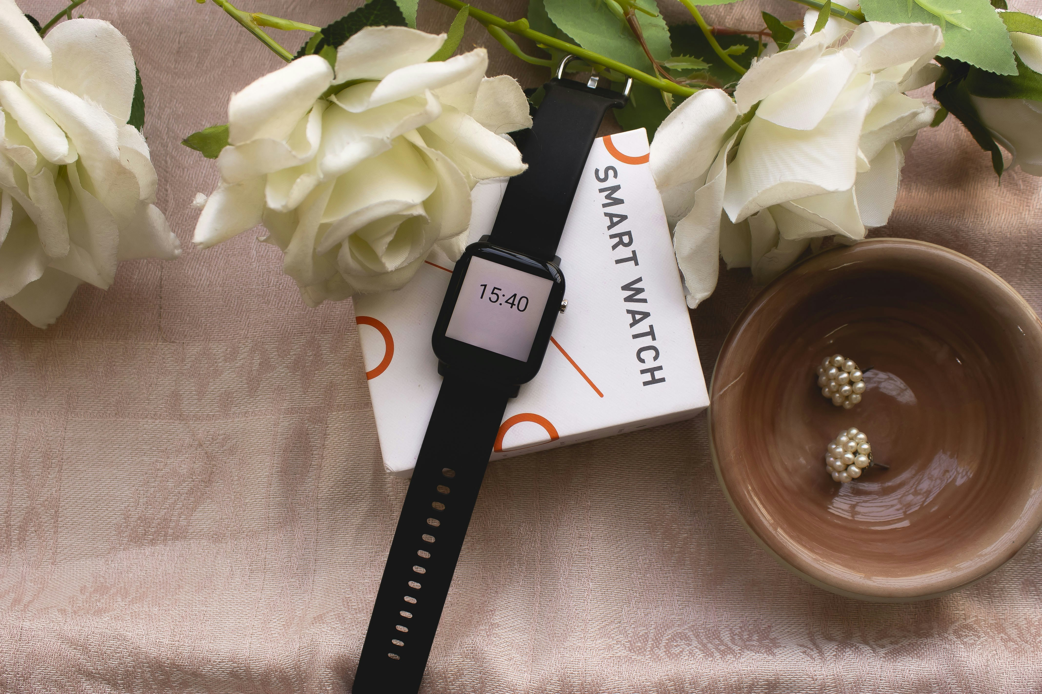 Petals and Time: A Smartwatch Resting Between Roses on Silk
