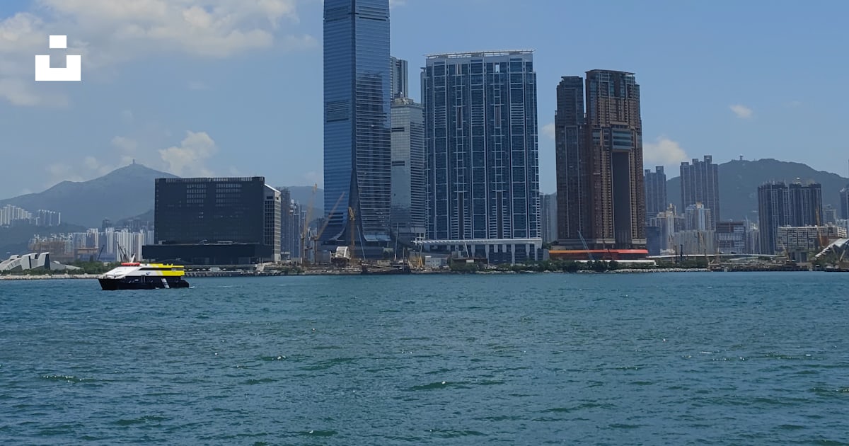 낮 동안 도시 건물 근처의 바다에 하얀 보트 사진 Unsplash의 무료 西九 이미지