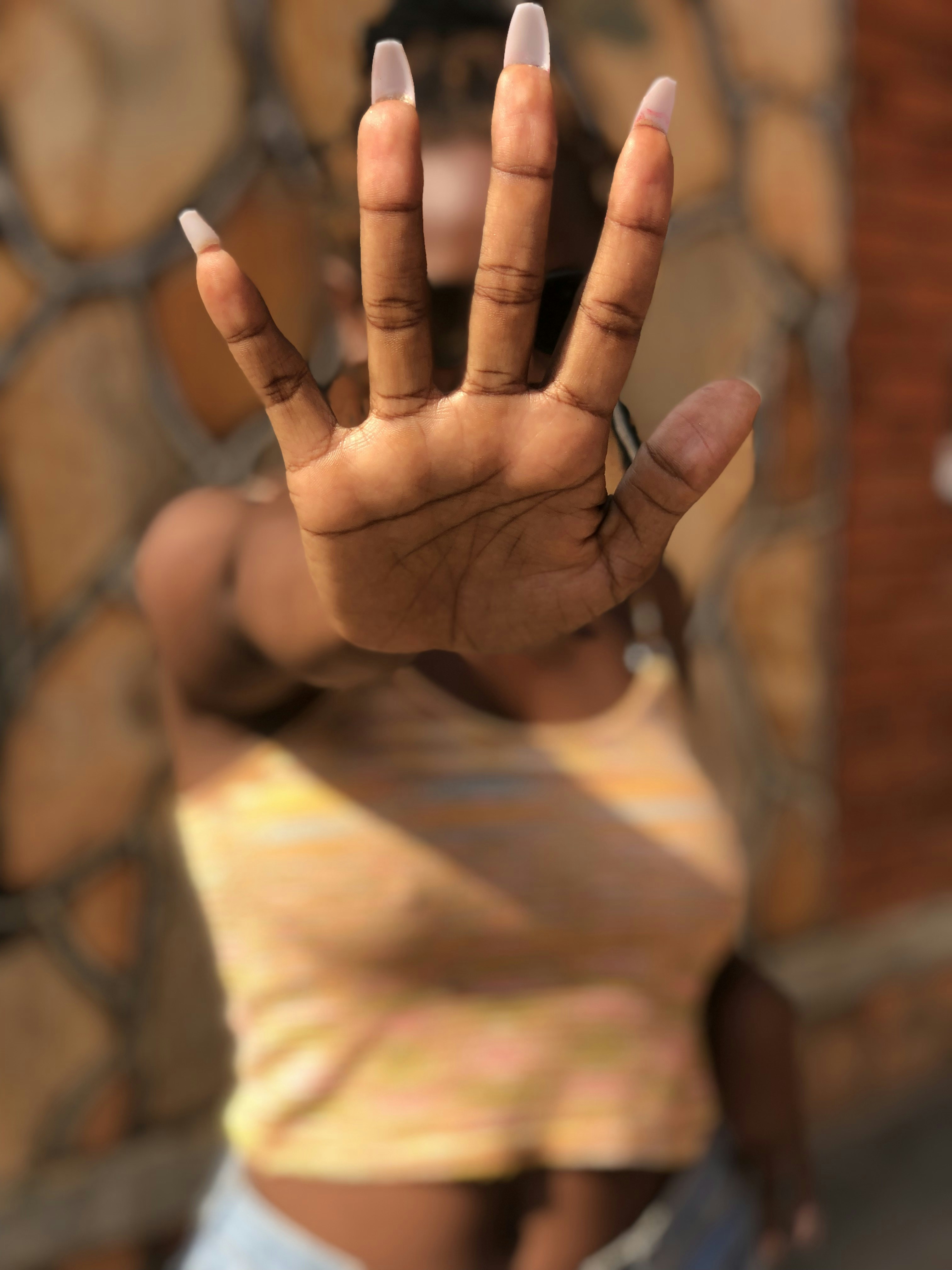 A hand raised in a gesture of refusal with a blurred background, emphasizing the subject's expression. The scene captures a moment of personal space and boundary setting.