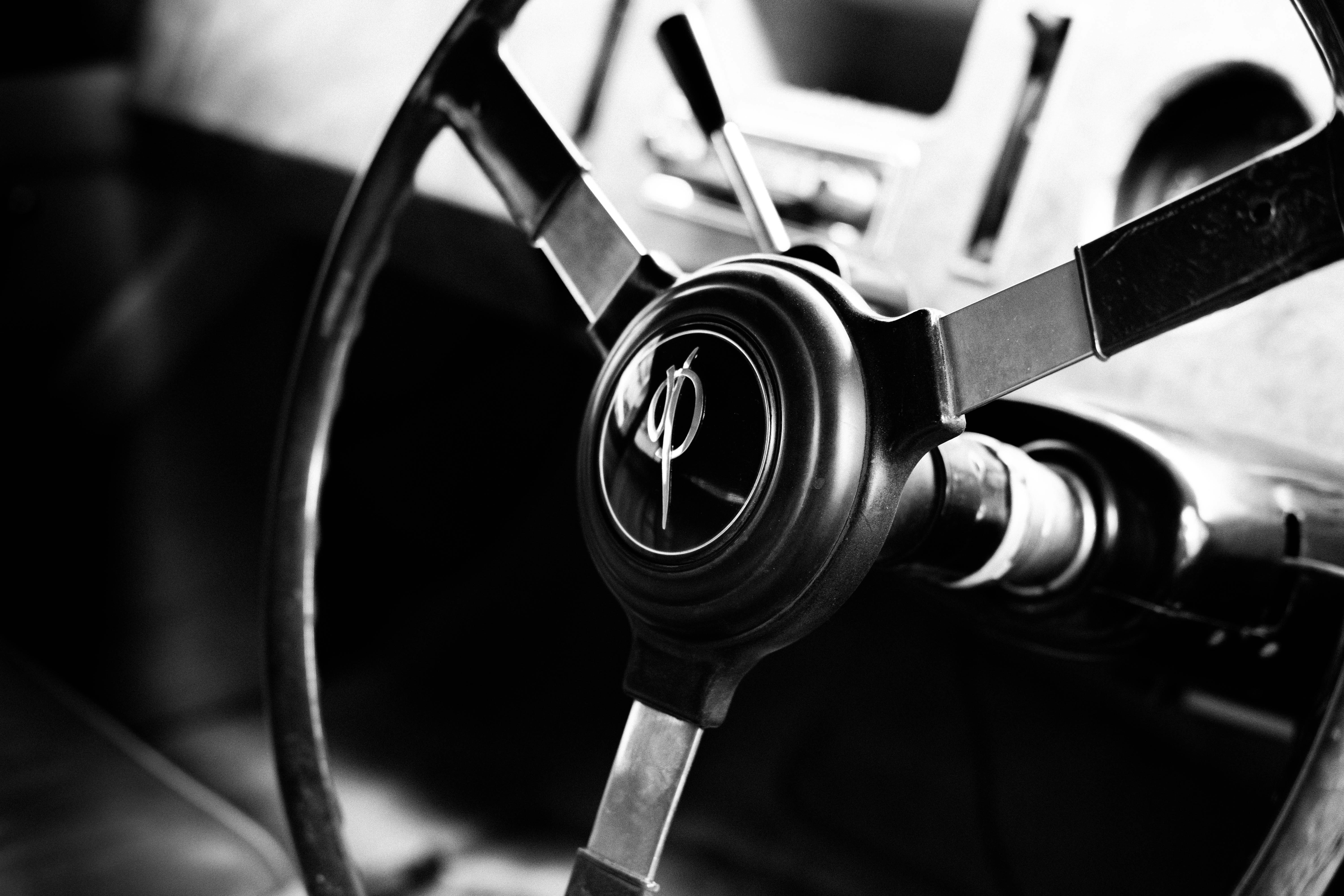 Monochrome cockpit centerpiece: weathered vintage steering wheel in a silent car