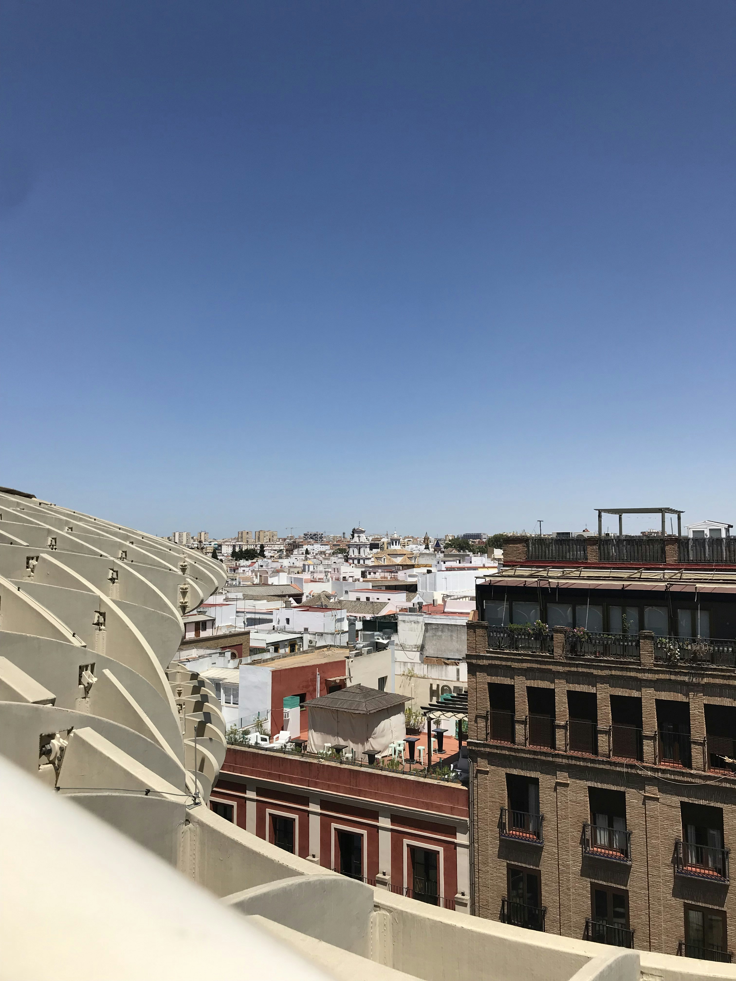 A panoramic view capturing the rooftops of a vibrant city under a clear blue sky, showcasing a mix of architectural styles and colors.