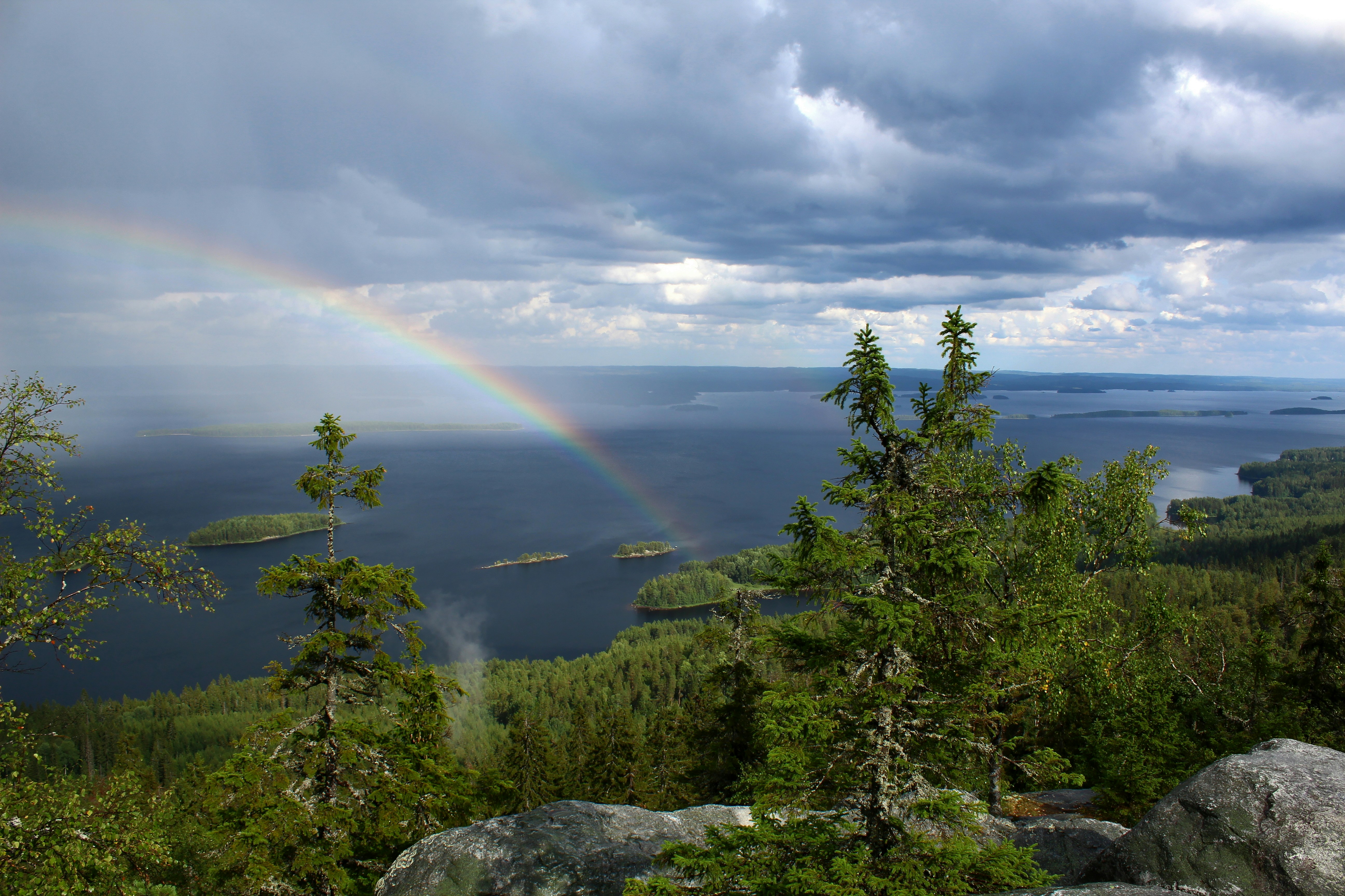 Rainbow over the pine-dotted promontory above a tranquil lake