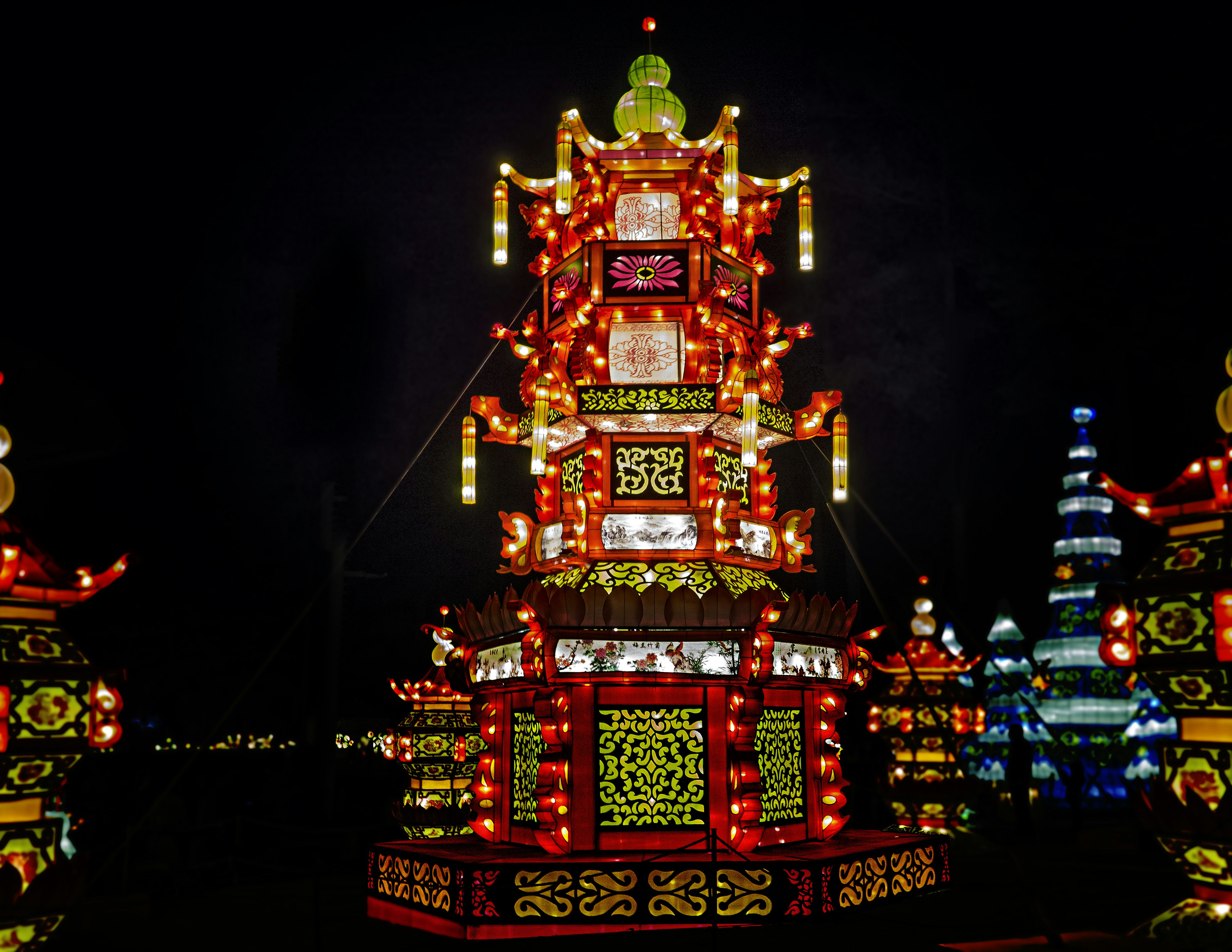 Vibrantly lit pagoda adorned with intricate patterns during a lantern festival at night.