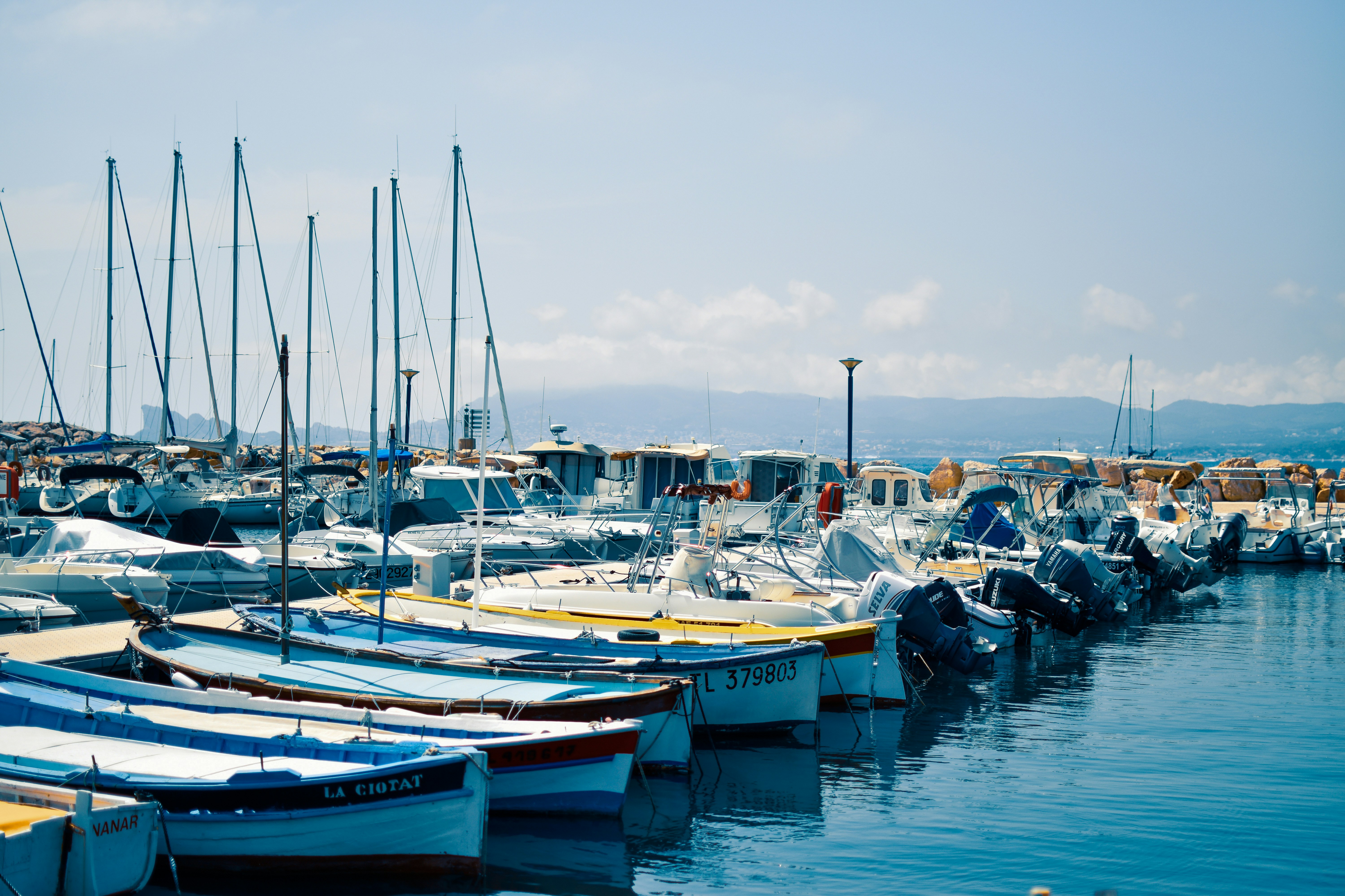 Row of boats docked in a peaceful harbor under a clear blue sky.