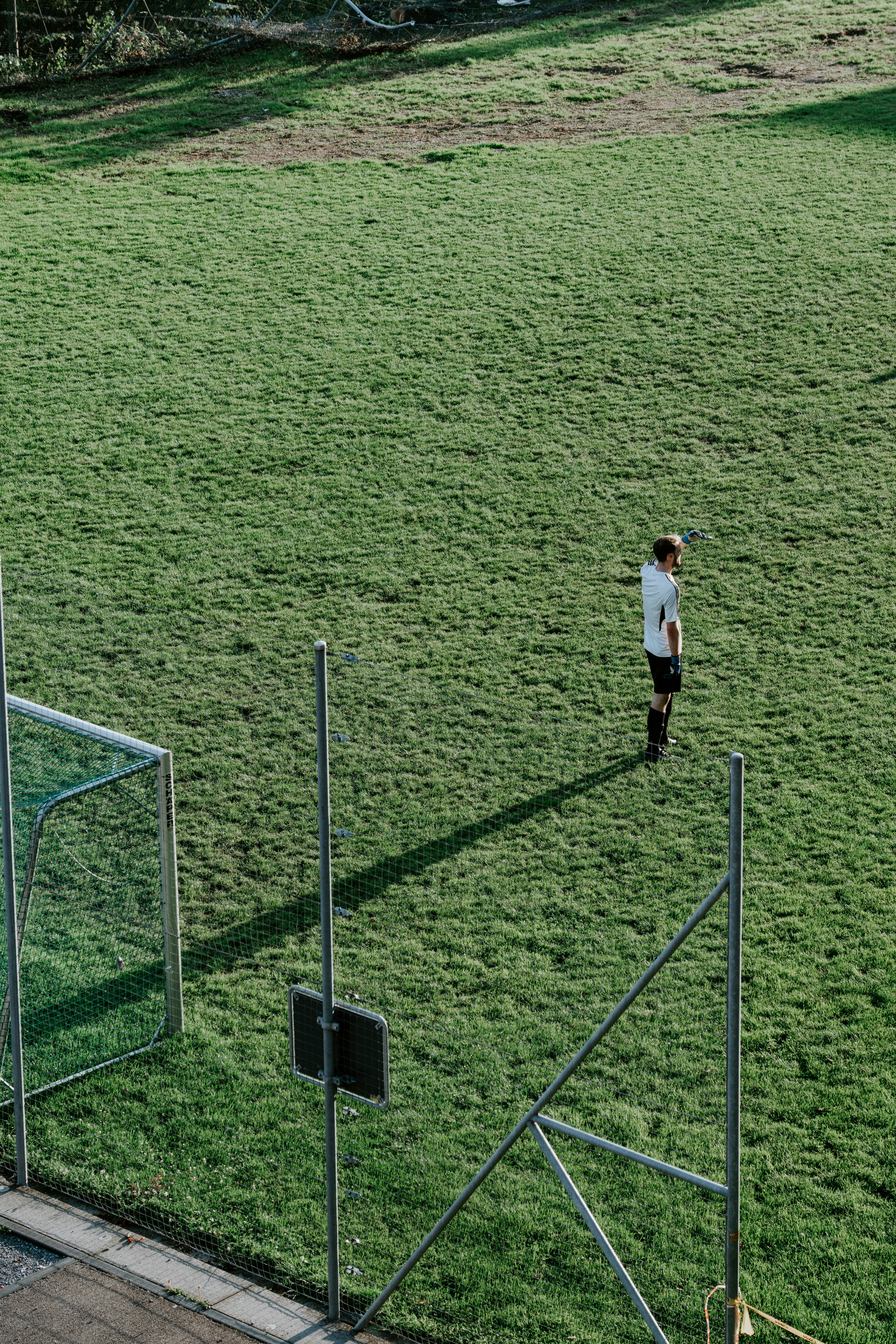 Above the Quiet Field: A Lone Soccer Player Stands in Sunlit Grass
