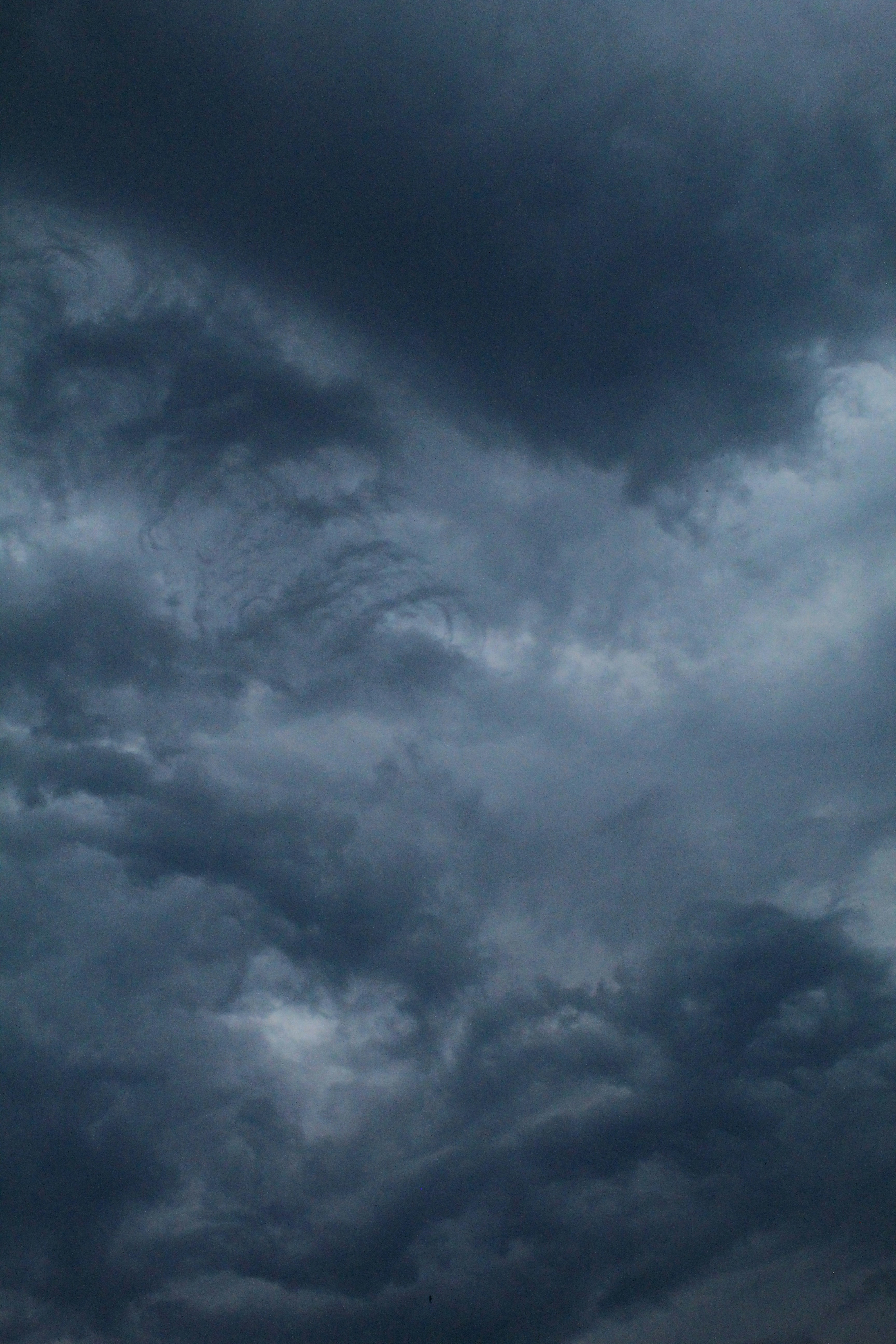 Dramatic clouds swirl together, hinting at an approaching storm. The varying shades of gray create a moody atmosphere.