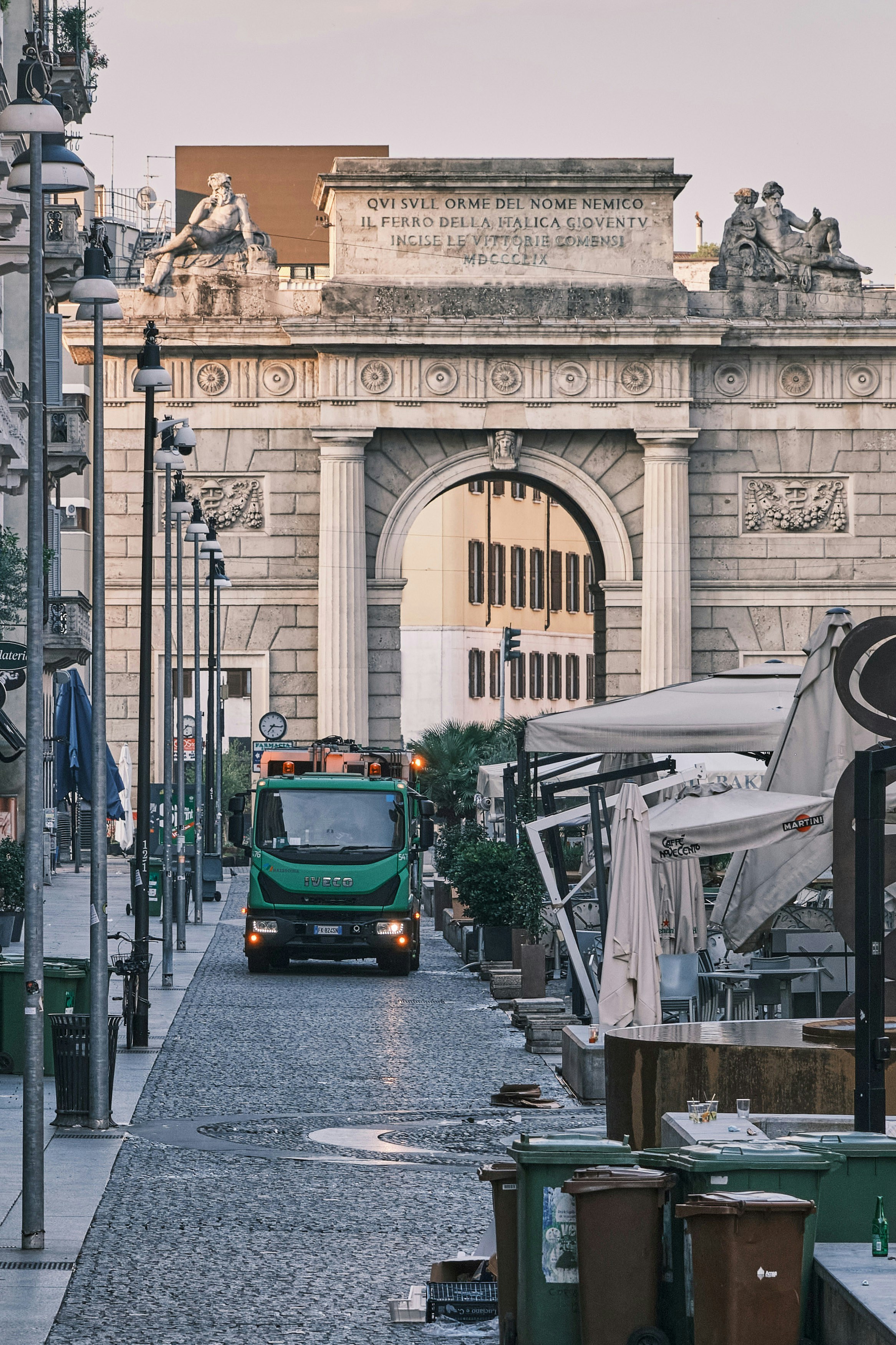 Green Hauler Under a Timeworn Archway on a Cobblestone Street