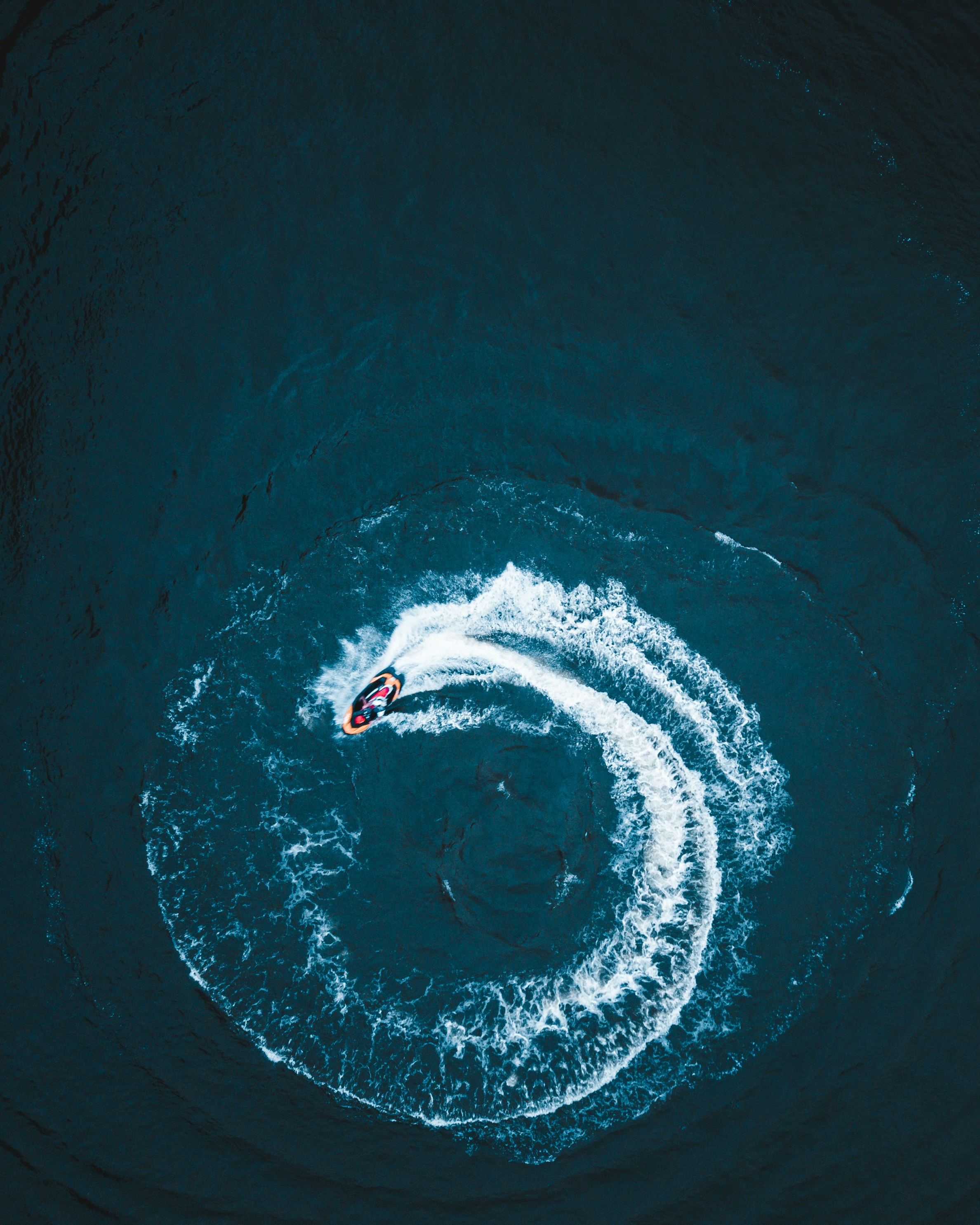 Aerial Spiral: Jetski Traces a Perfect Ring Across Deep Blue Ocean