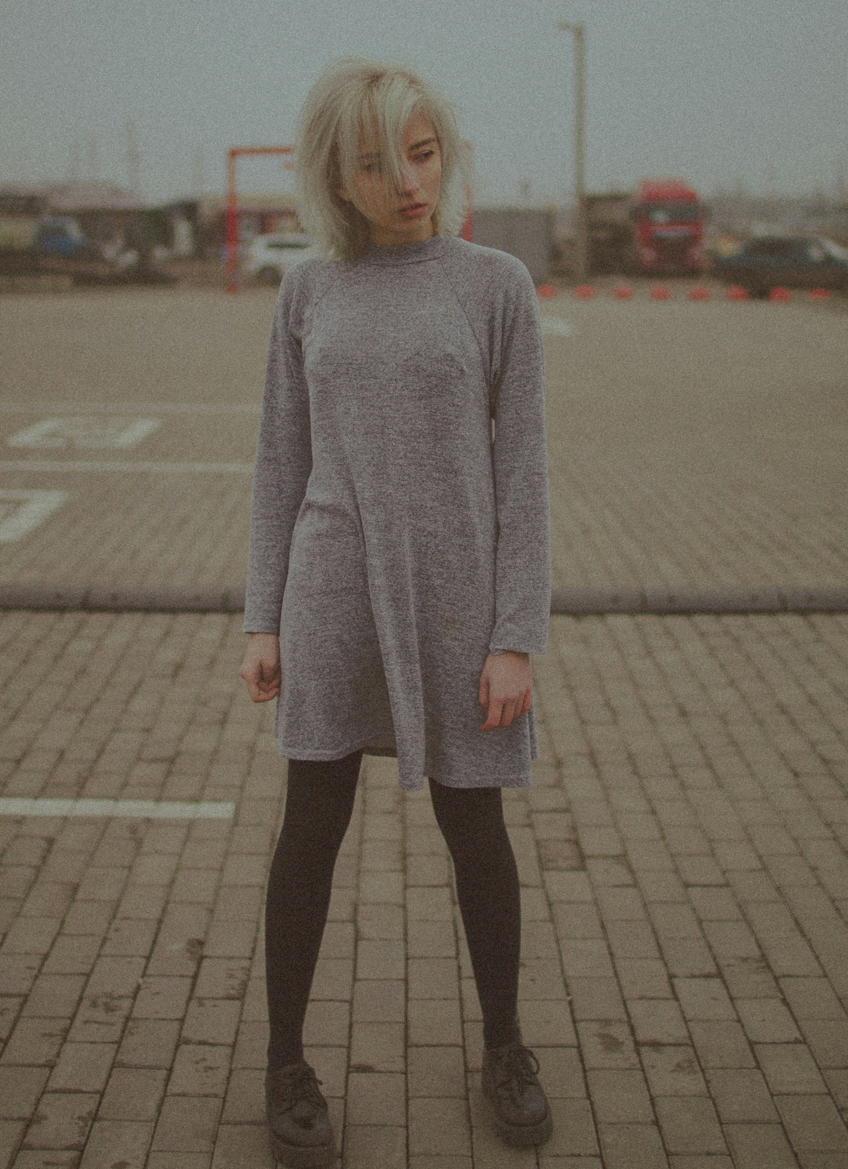 woman in gray sweater standing on gray concrete road during daytime