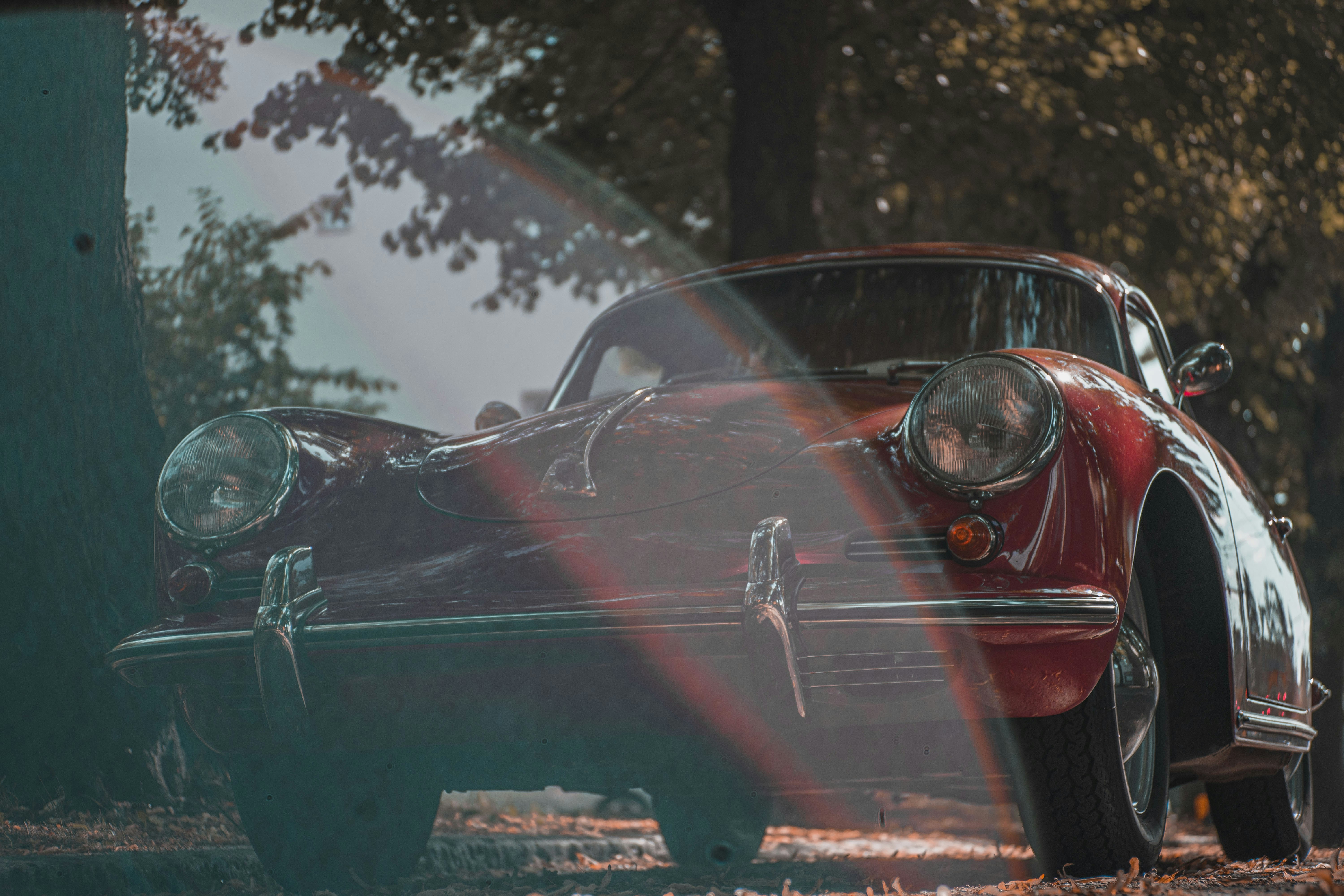 Sunlit Curves: A 1960s Red Classic Under a Diagonal Lens Flare
