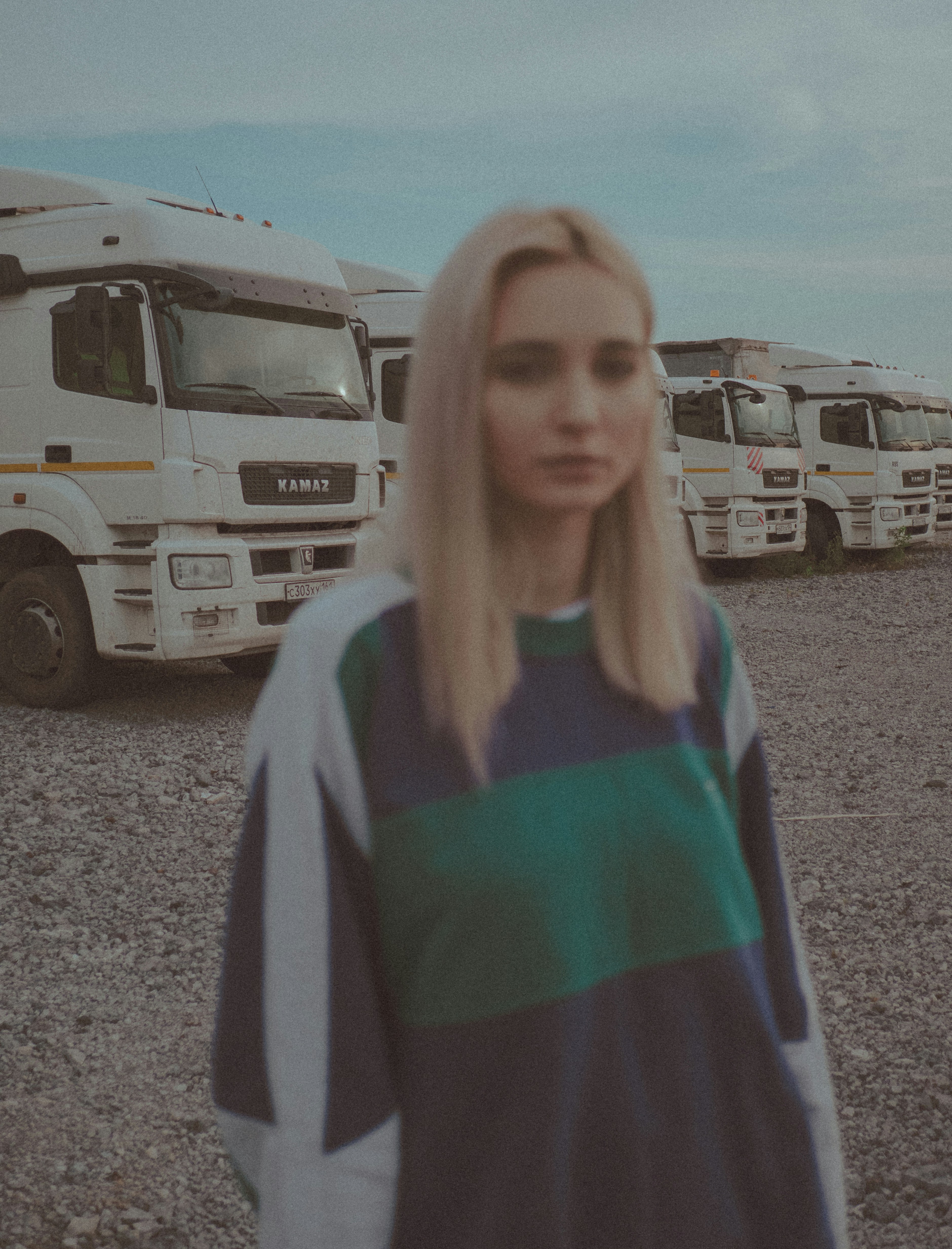 Blurry Portrait Among Rigs: A Quiet Moment in a Truck Yard