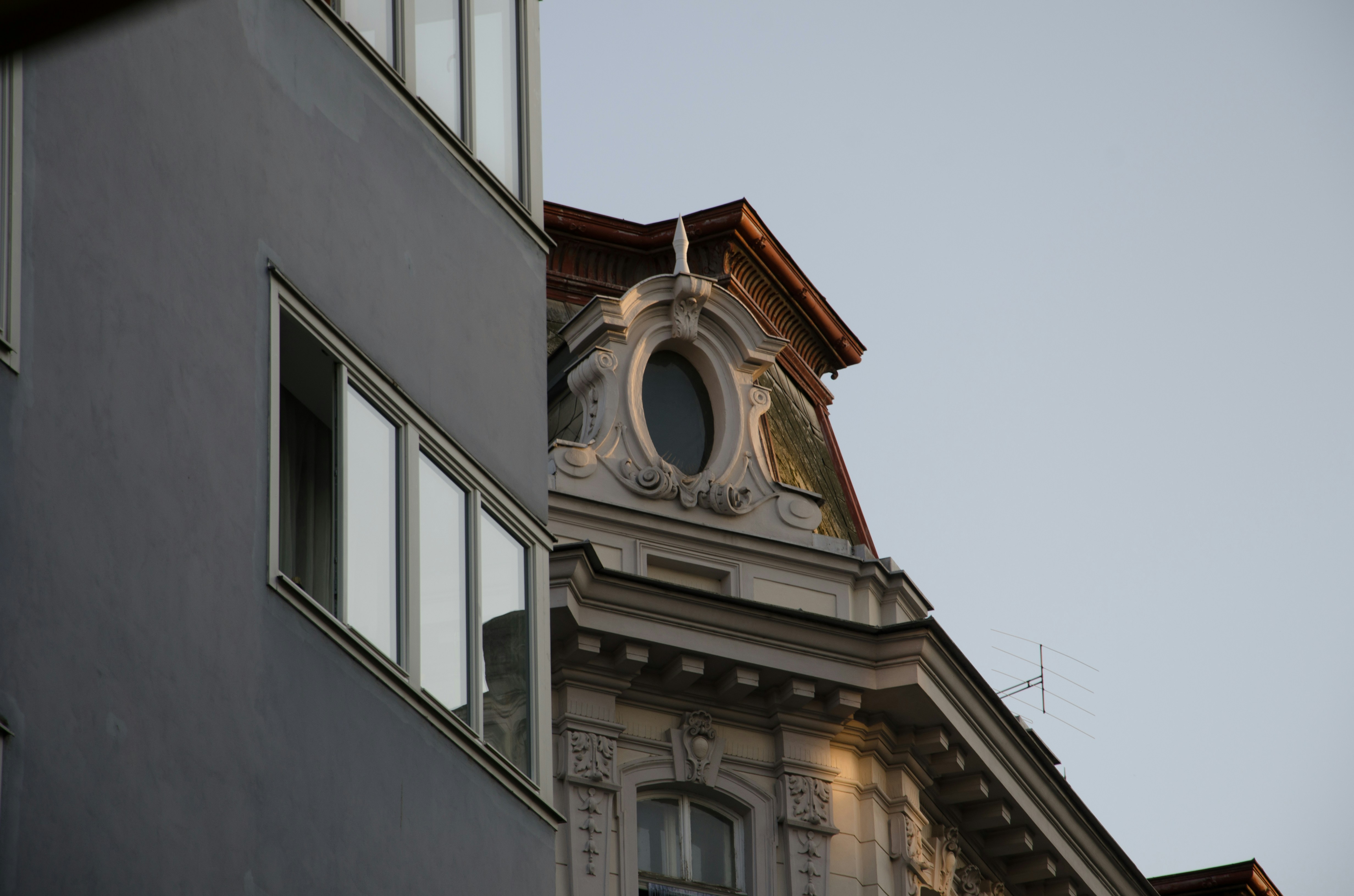 Intricate architectural details of a historic building contrasted against a modern facade. The ornate window showcases craftsmanship from a bygone era.