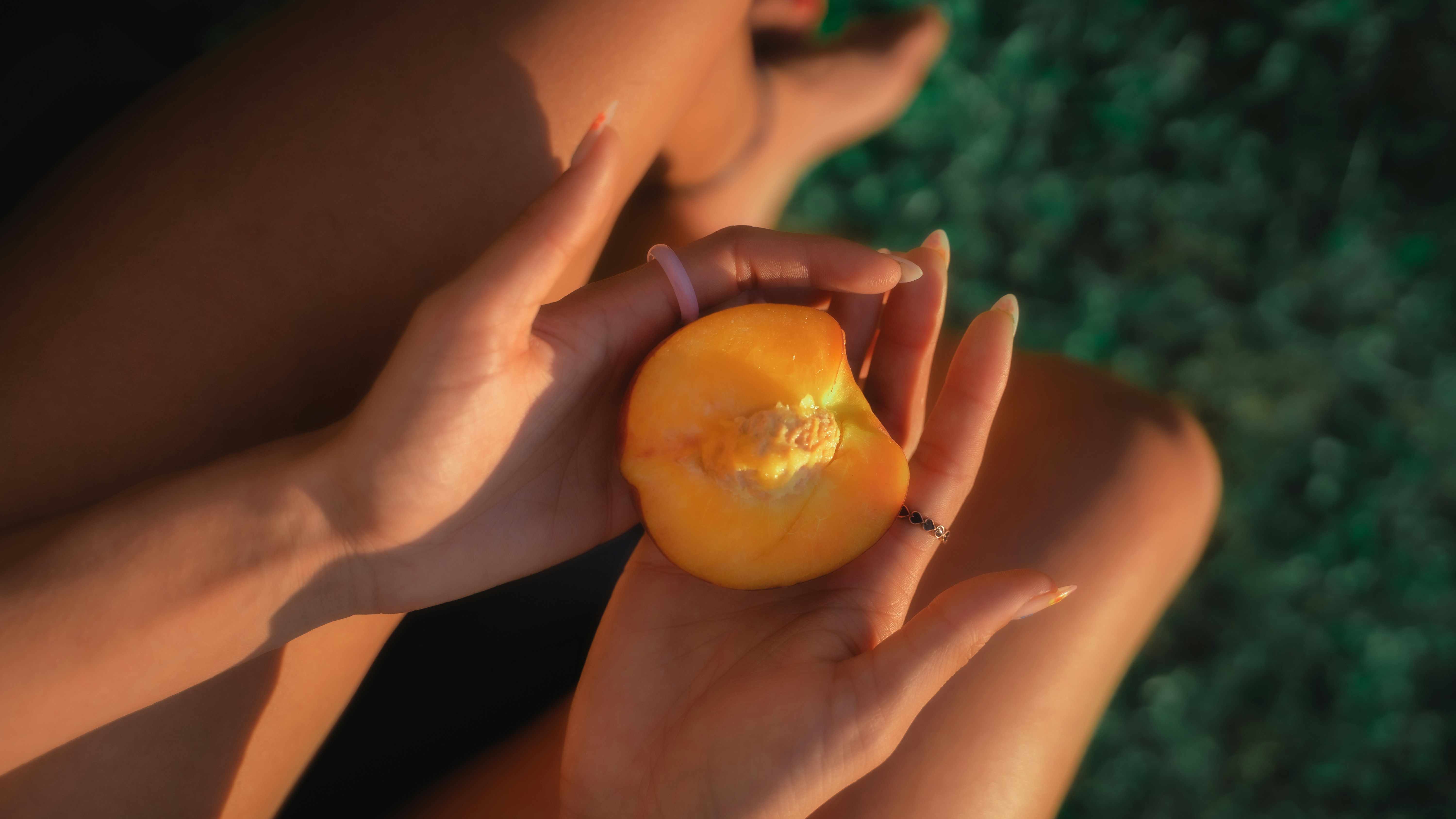 Cradled Peach in Sunlit Hands Against Verdant Blur