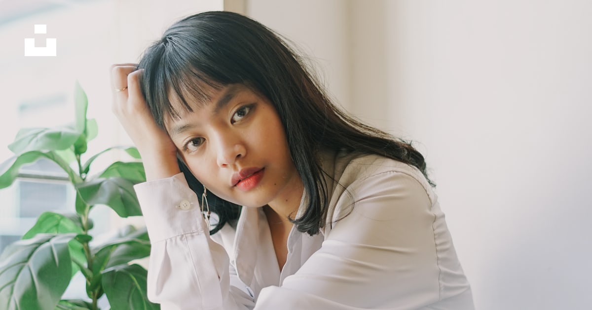 녹색 식물 옆에 앉아 흰색 긴 소매 셔츠를 입은 여자 사진 Unsplash의 무료 사진술 이미지