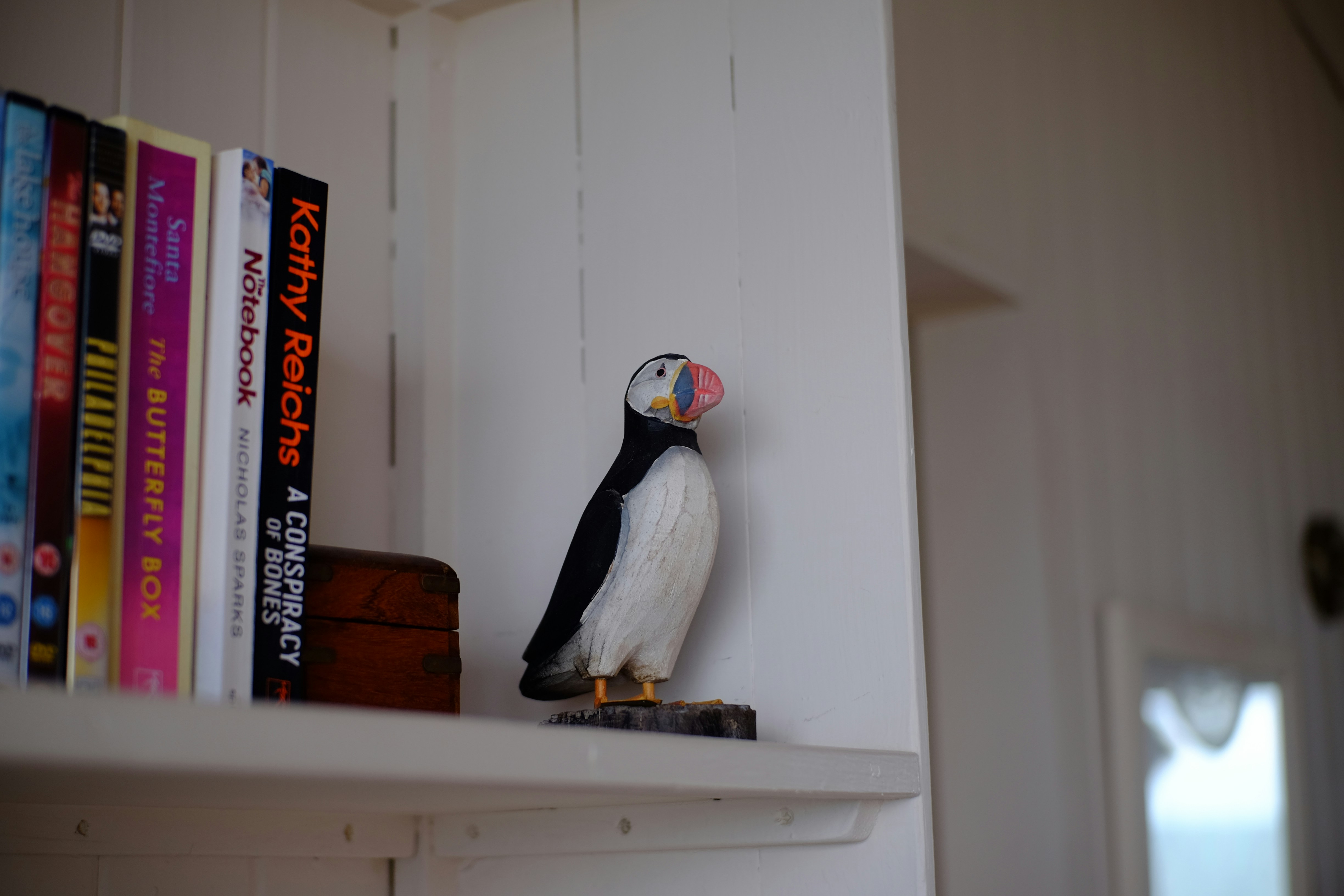 Shelved Sentinel: Ceramic Puffin Guards a Quiet Reading Shelf