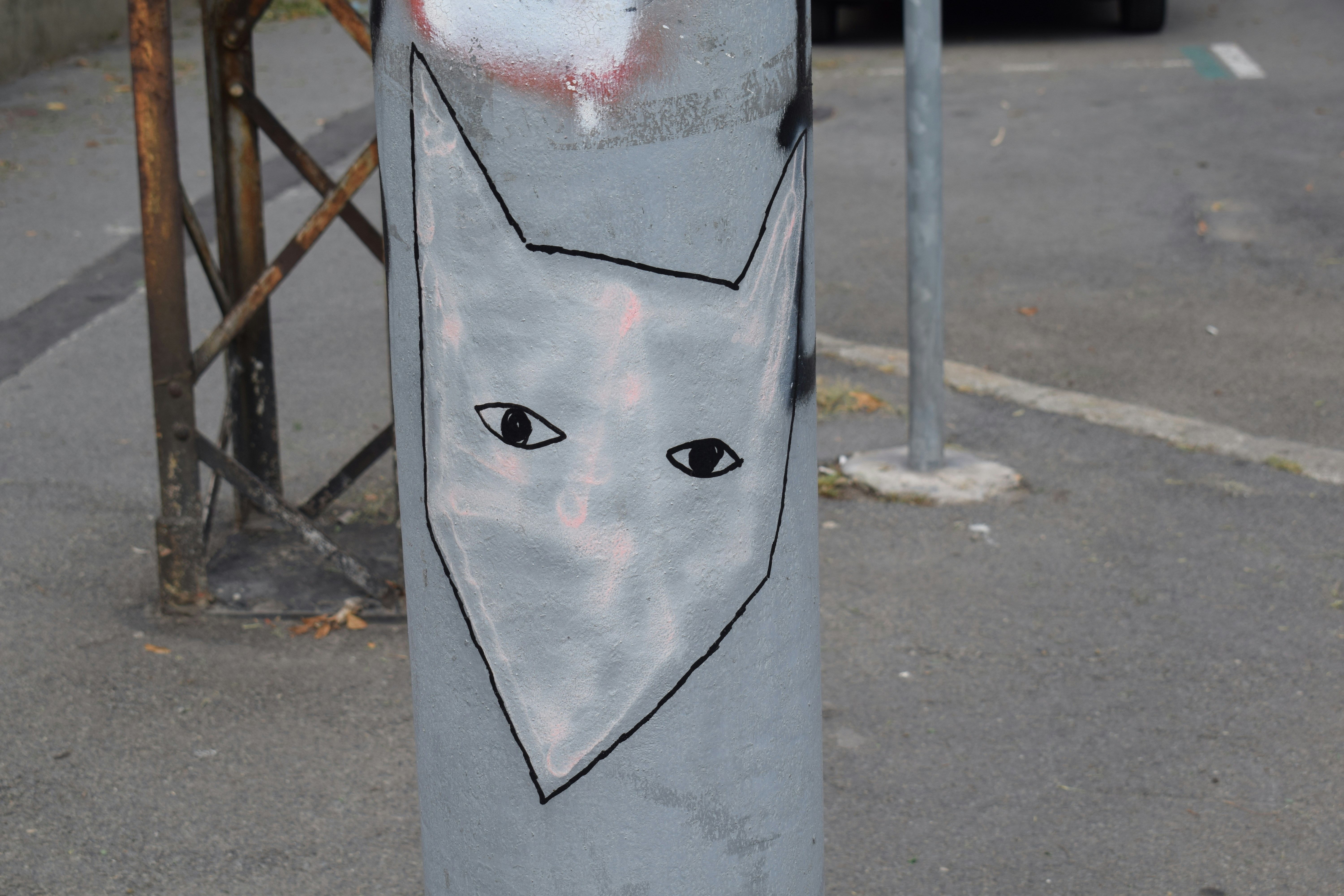 The Masked Eye: Graffiti Portrait on a Weathered Street Pole