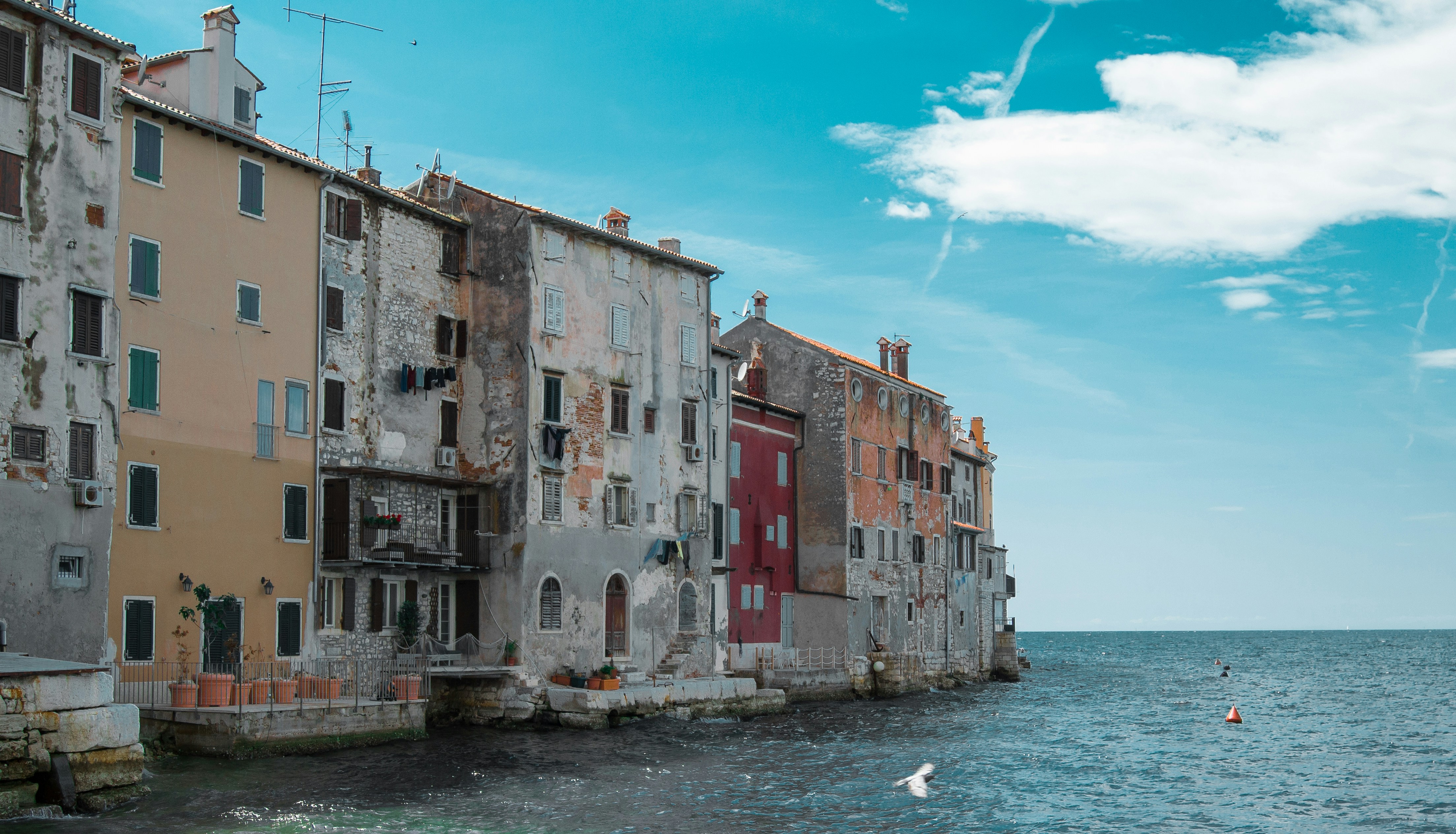 Charming, weathered buildings line the waterfront of Rovinj, showcasing a blend of colors and textures against a serene sea backdrop.