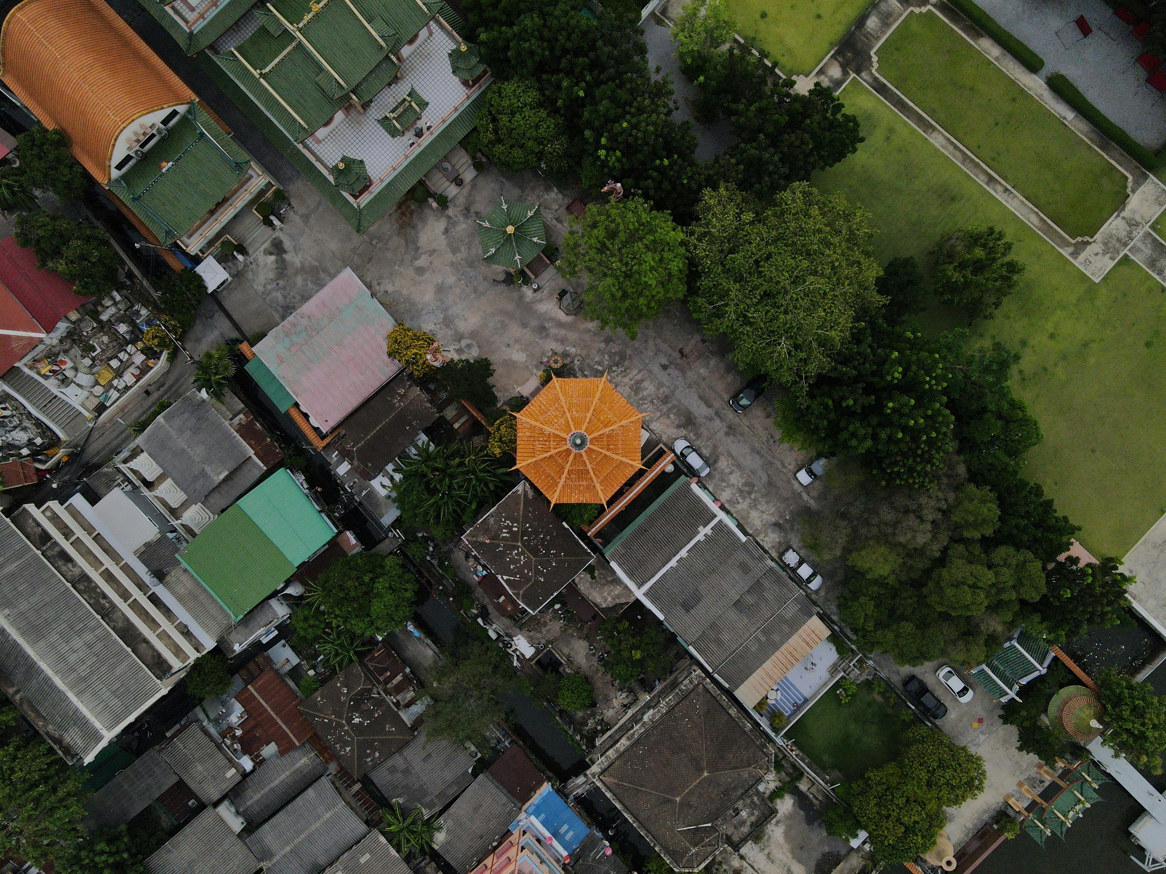 Aerial view of a vibrant urban area featuring a distinct pagoda structure surrounded by greenery and residential buildings. The layout reveals a blend of architecture and nature.