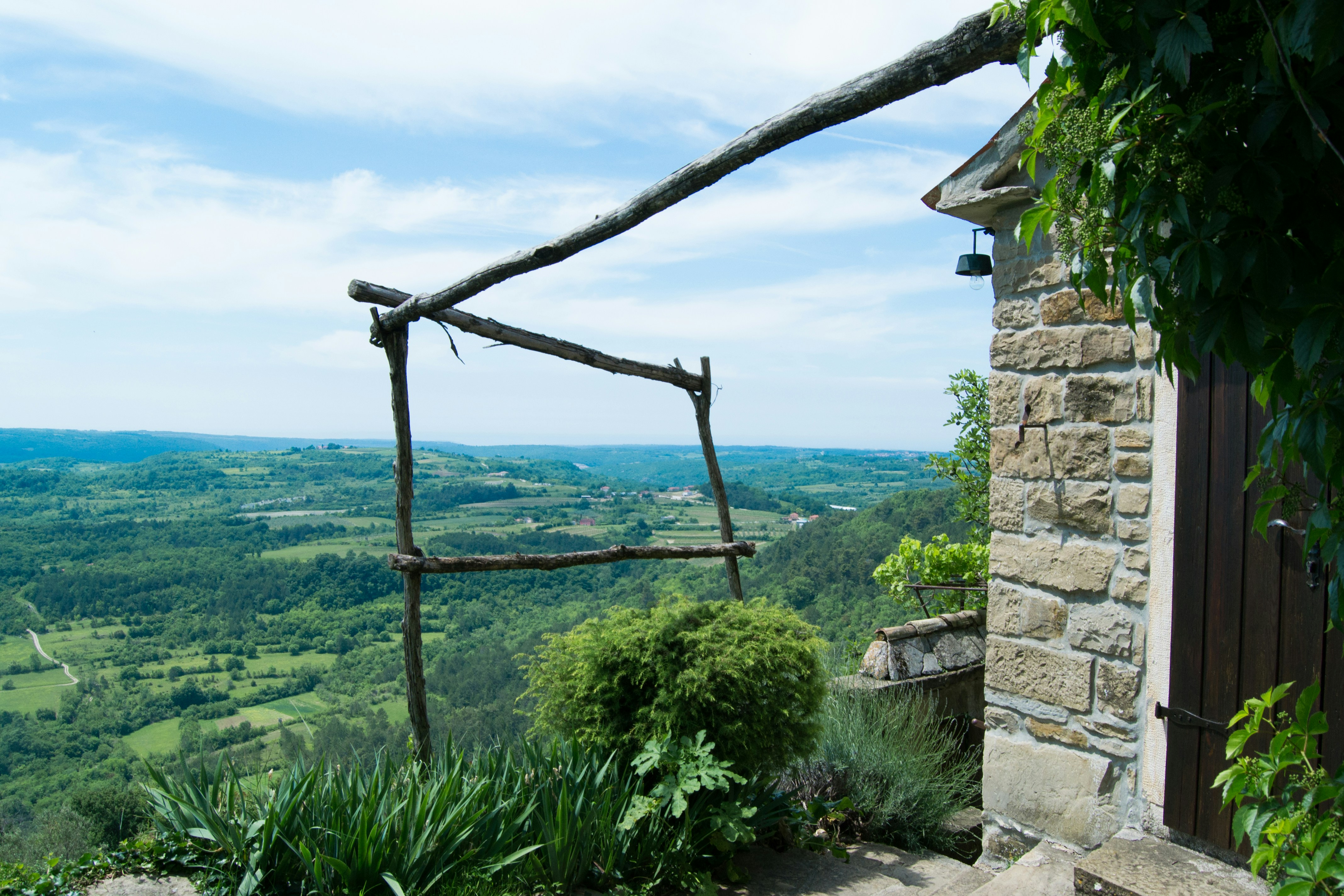 Rustic wooden frame overlooking a lush green valley under a bright sky, showcasing the harmony between architecture and nature.