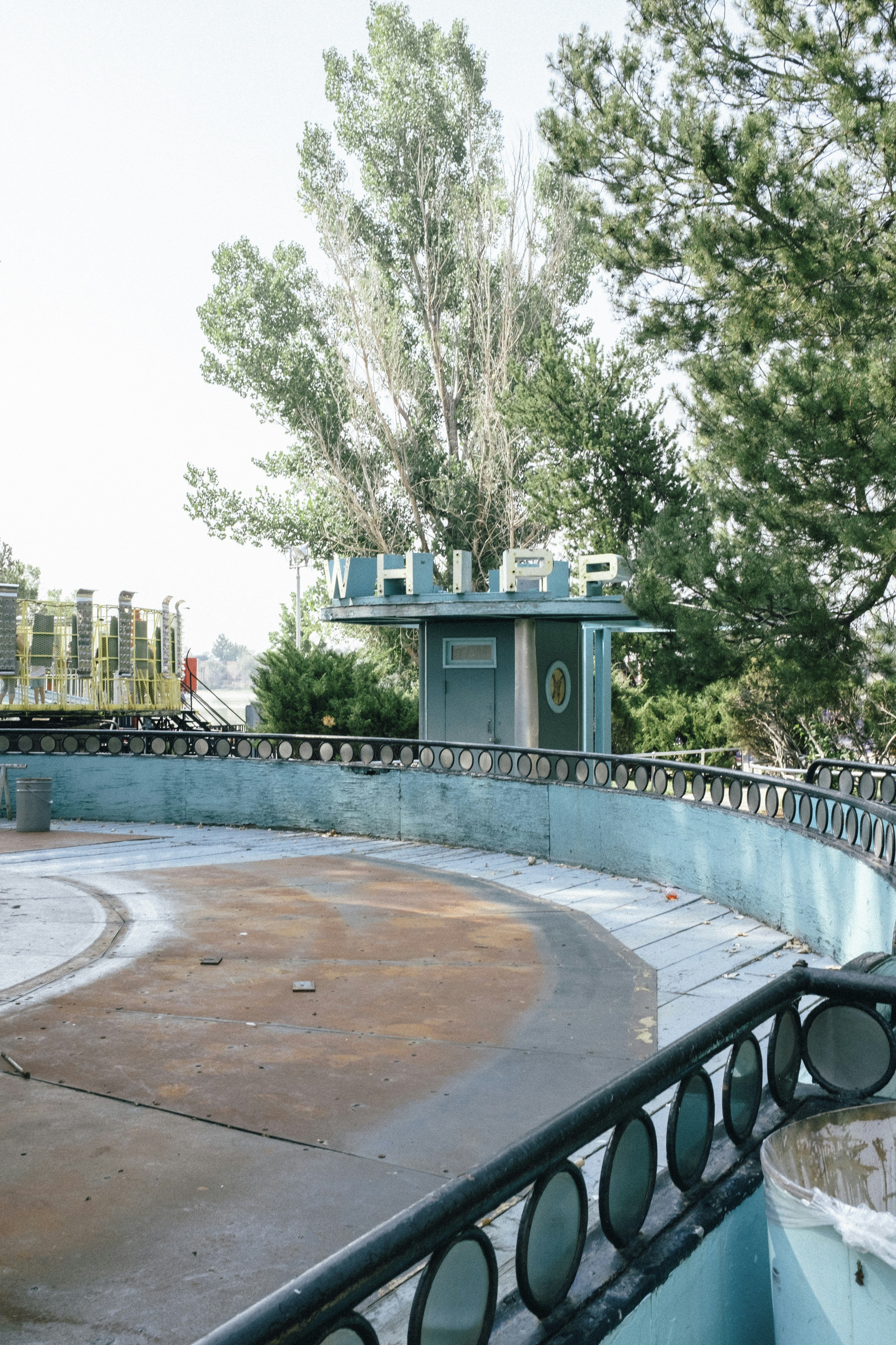 Blue Whirl Booth at the Quiet Park: A Forgotten Sign Above an Empty Plaza