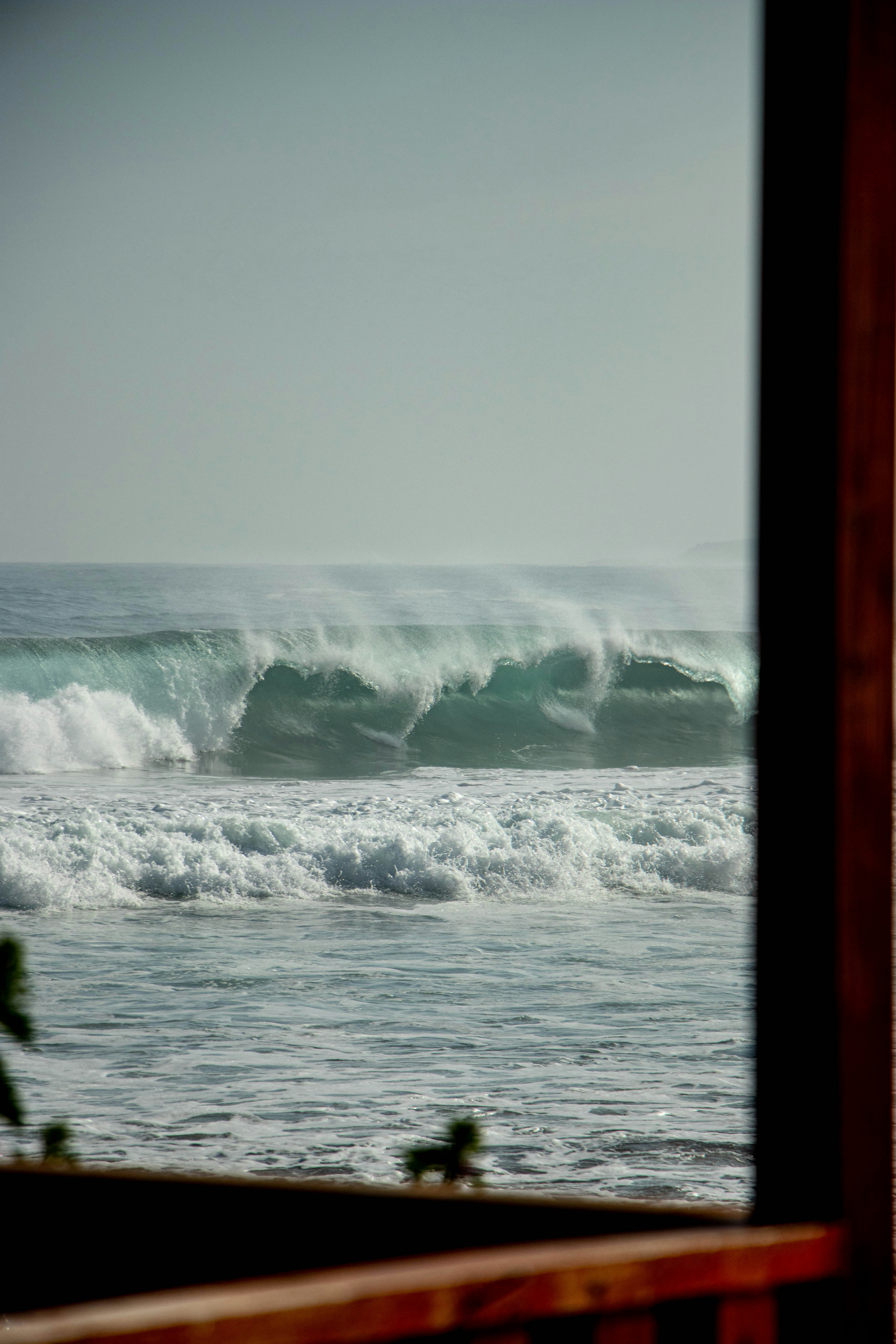 Window to the surf: Sea waves framed by a wooden balcony