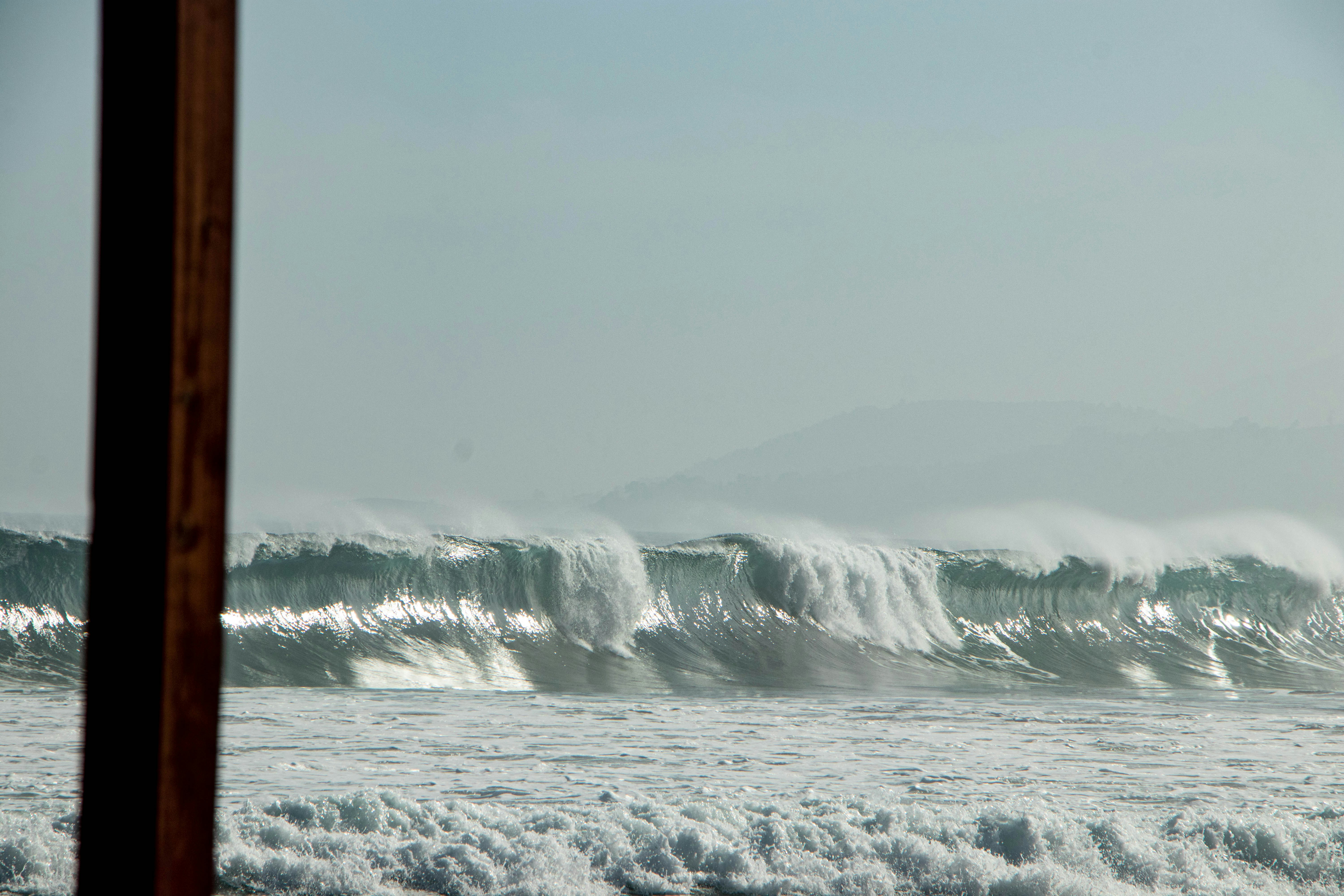 Framed Breakers: Cresting Waves Beyond a Weathered Pier