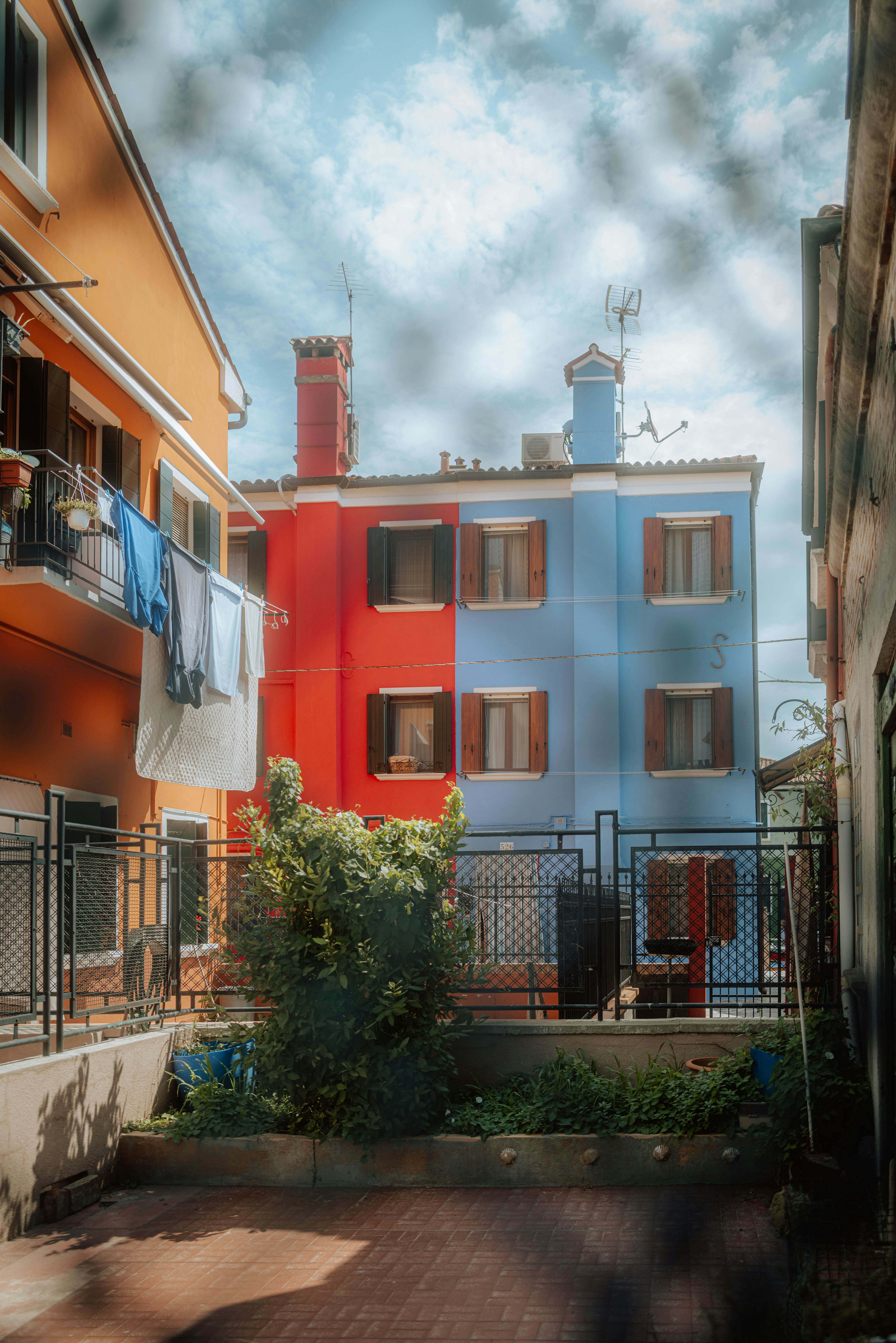 Courtyard in Color: The Red-Blue Facade Between Orange Neighbors