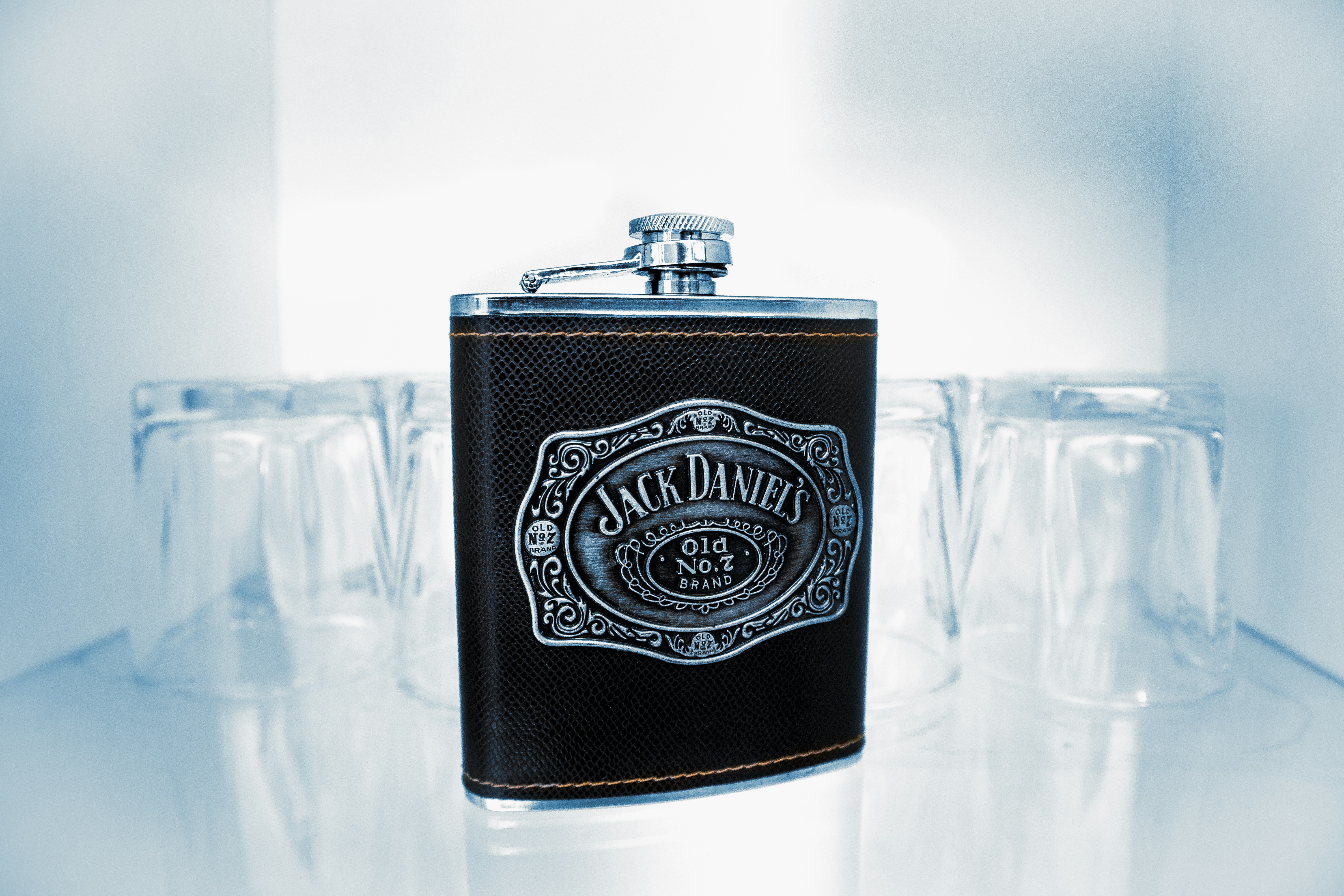 Centered Jack Daniel's Flask Bathed in Cobalt Glow on a Glass Shelf