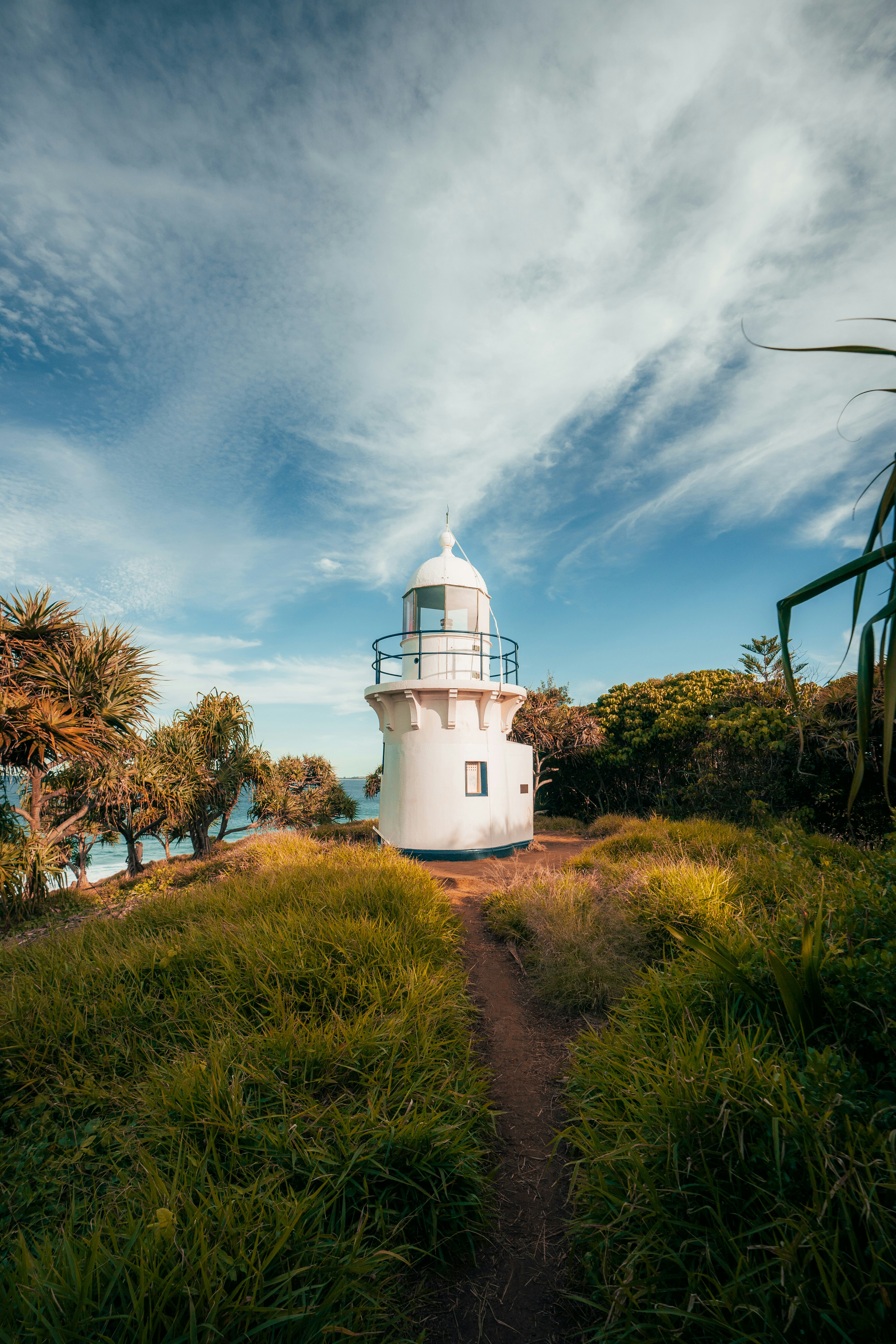 White lighthouse on green grass field under blue sky during daytime ...