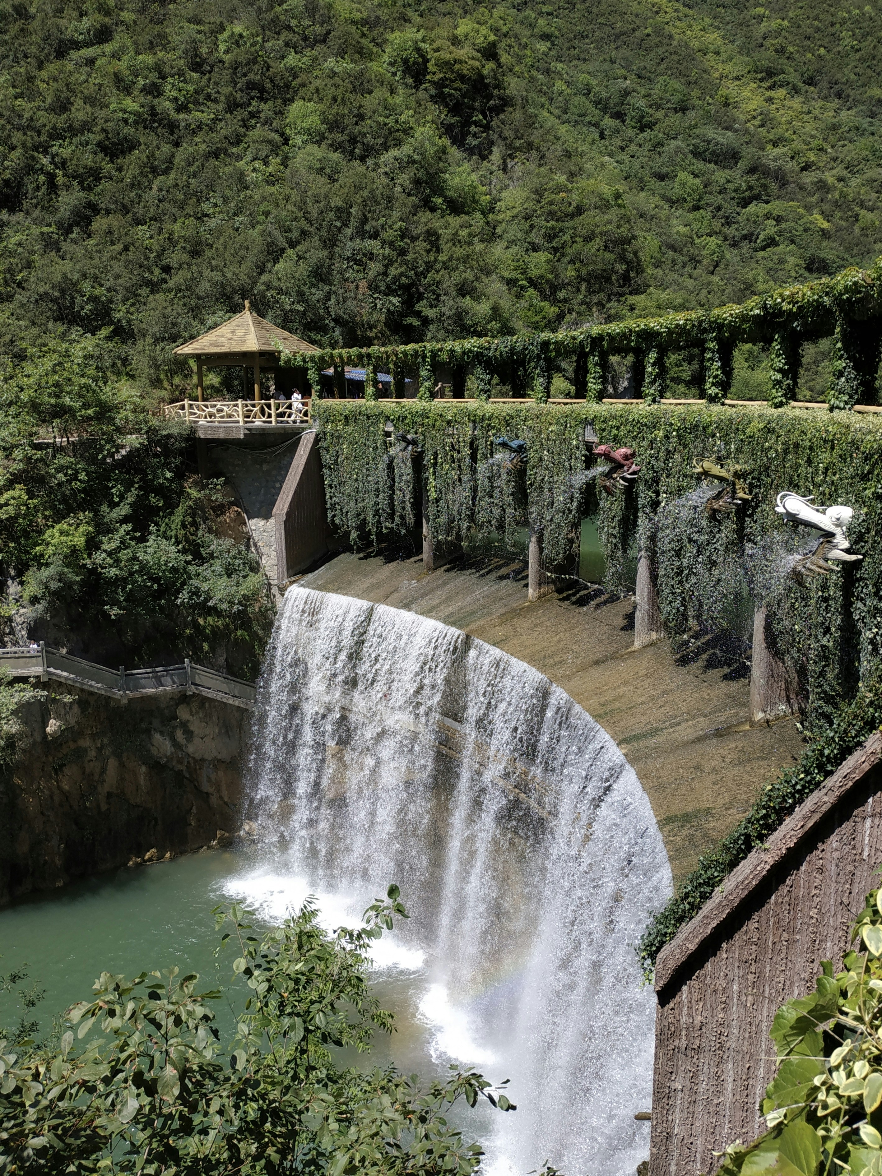 people standing on bridge over waterfalls during daytime