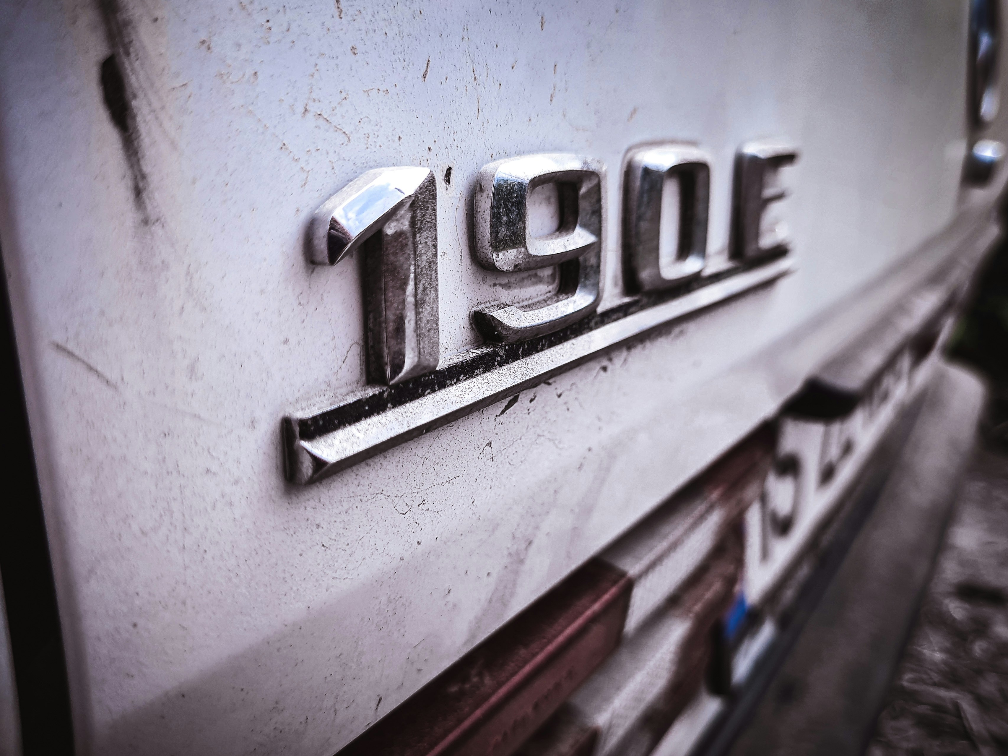 Dust-Kissed Chrome: The 190E Emblem on a Weathered Trunk
