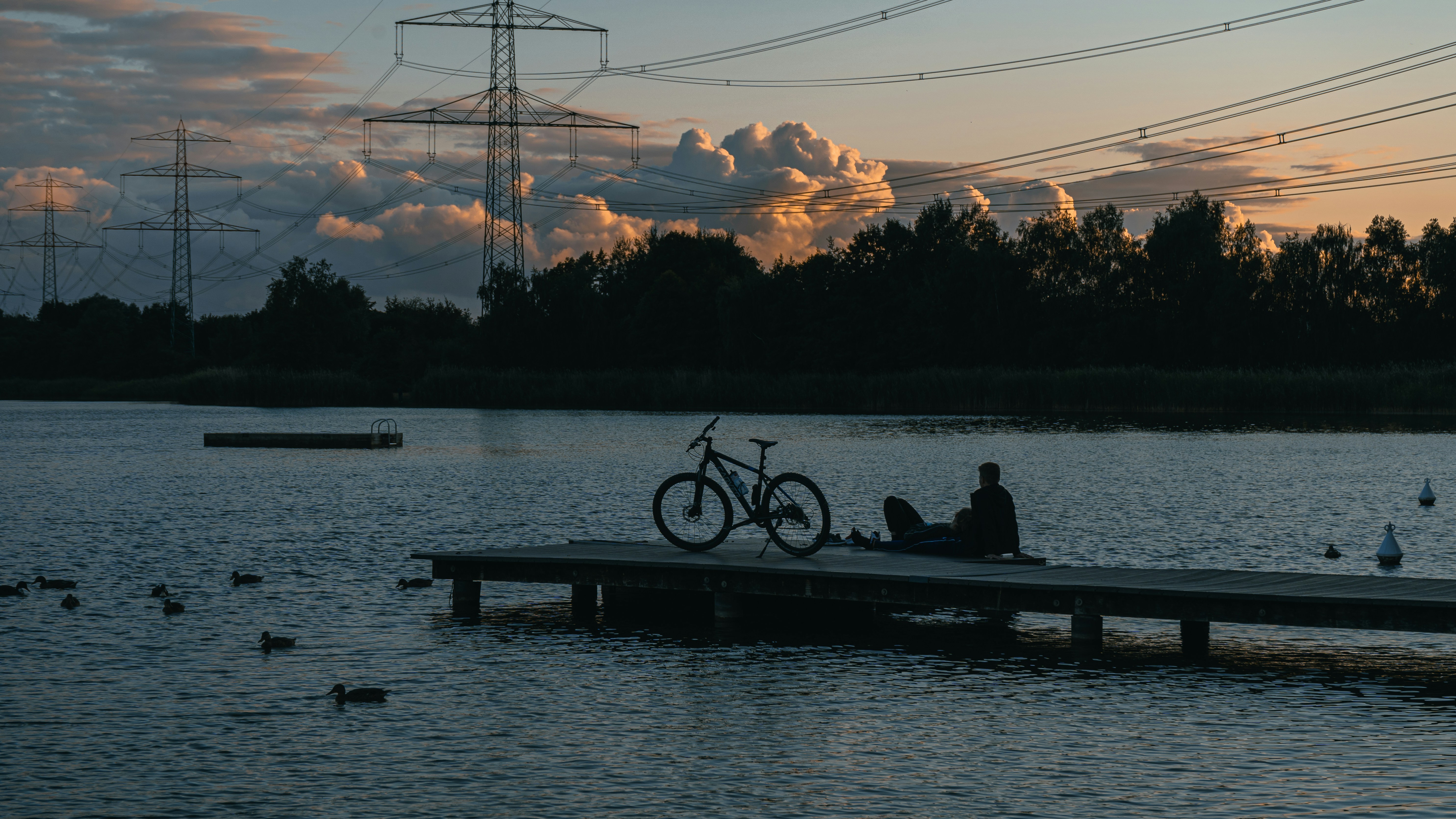 Dusk at the Lakeside Pier: A Lone Cyclist Pauses by the Water