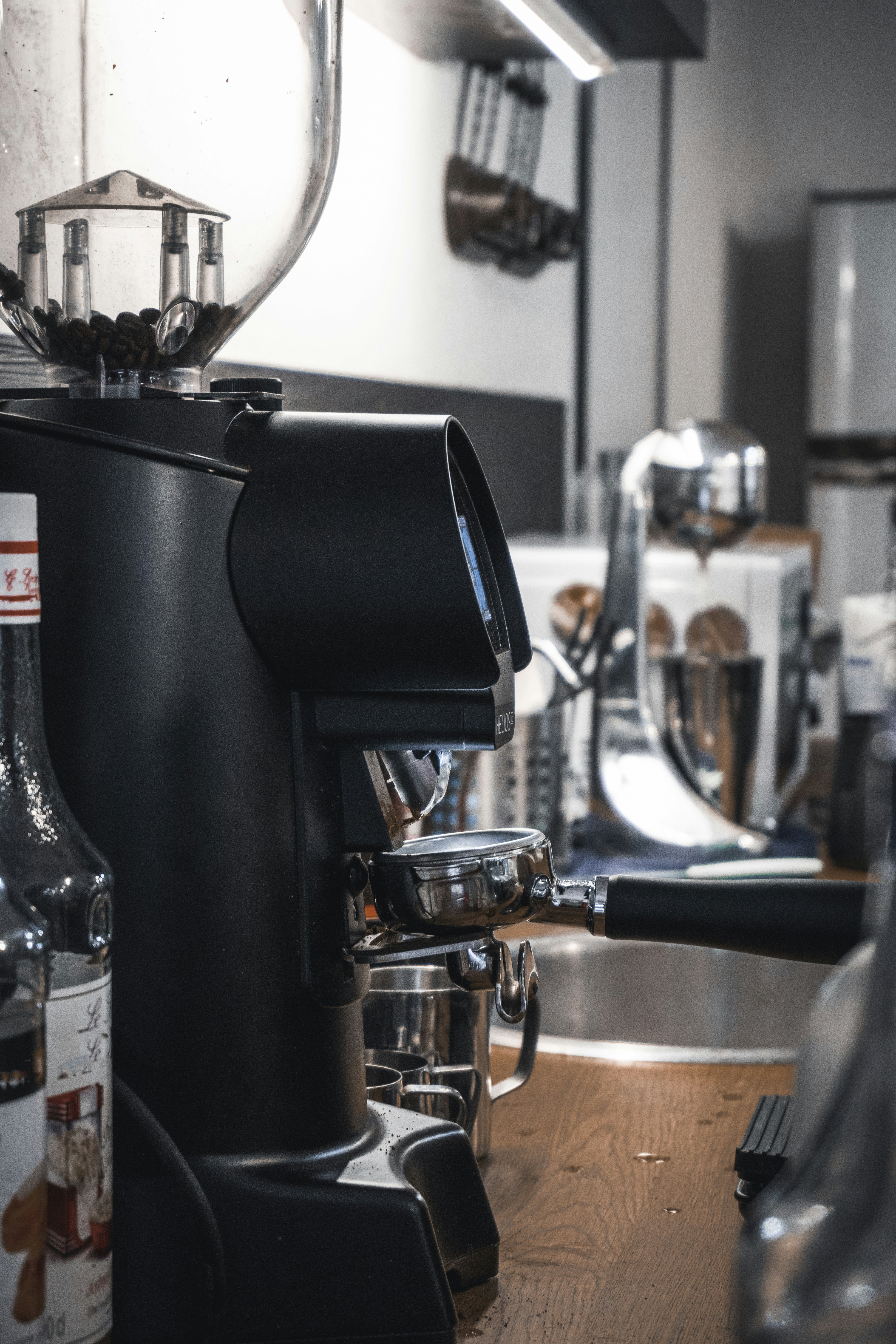 Close-up of an espresso machine with a portafilter in use, showcasing the intricate details of coffee preparation. The scene highlights the equipment and coffee beans in a modern cafe setting.