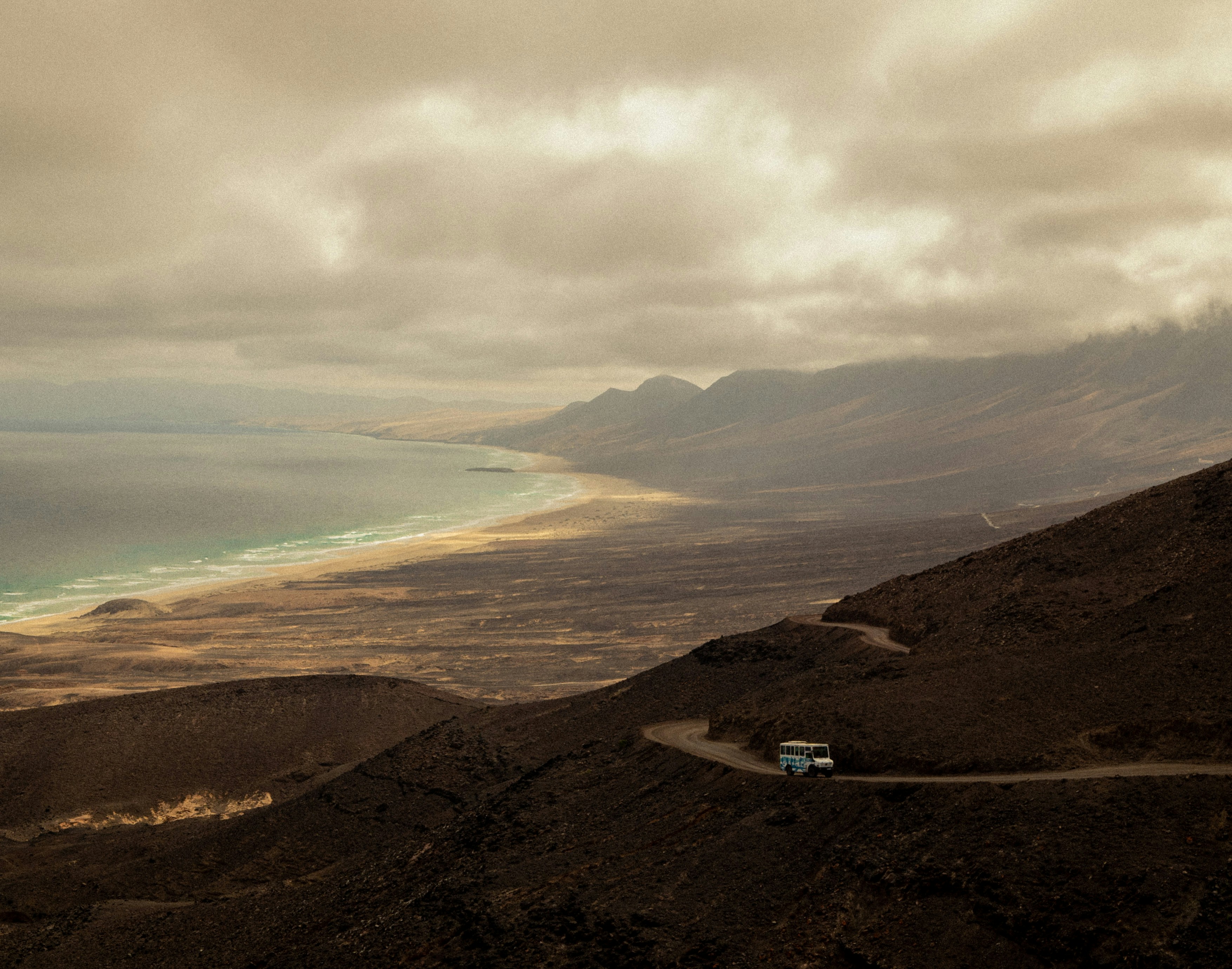 Serpentine Cliff Road by a Misty Coast, with a Lone White Vehicle