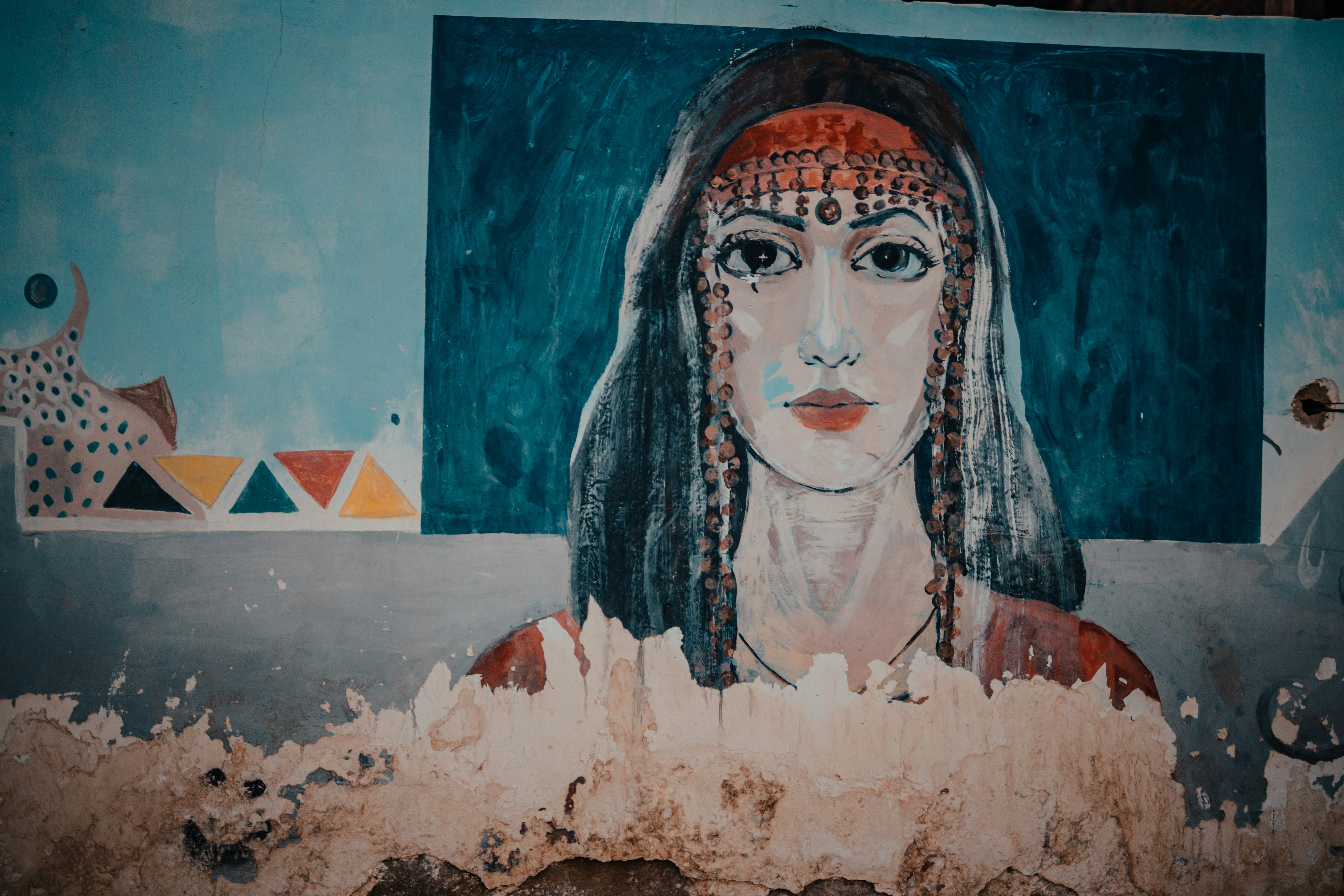 Portrait of a Painted Veil: A Woman with Beaded Headdress Emerges from Crumbling Turquoise Wall