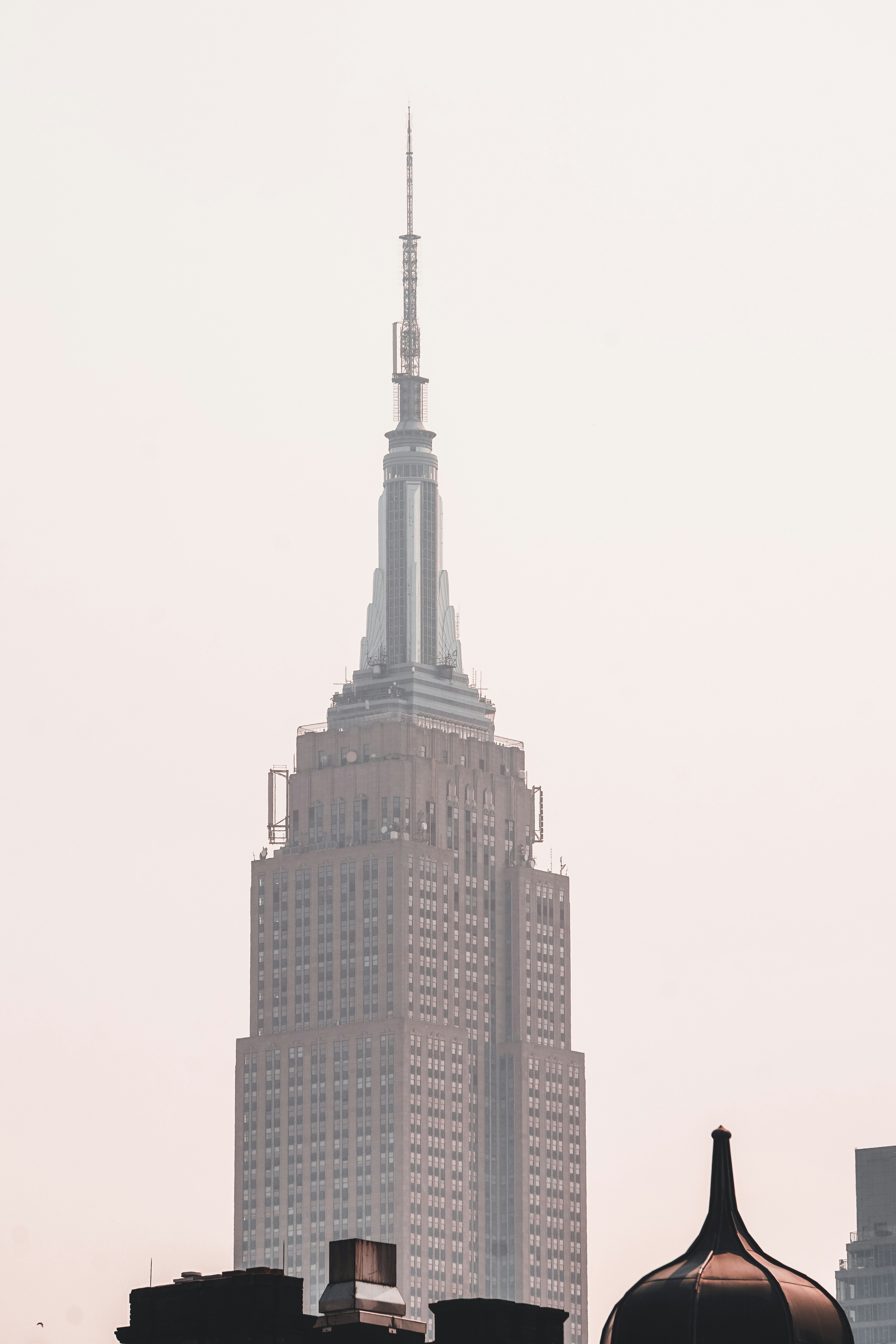 The Empire State Building rises majestically through a soft haze, showcasing its Art Deco architecture against a muted backdrop.