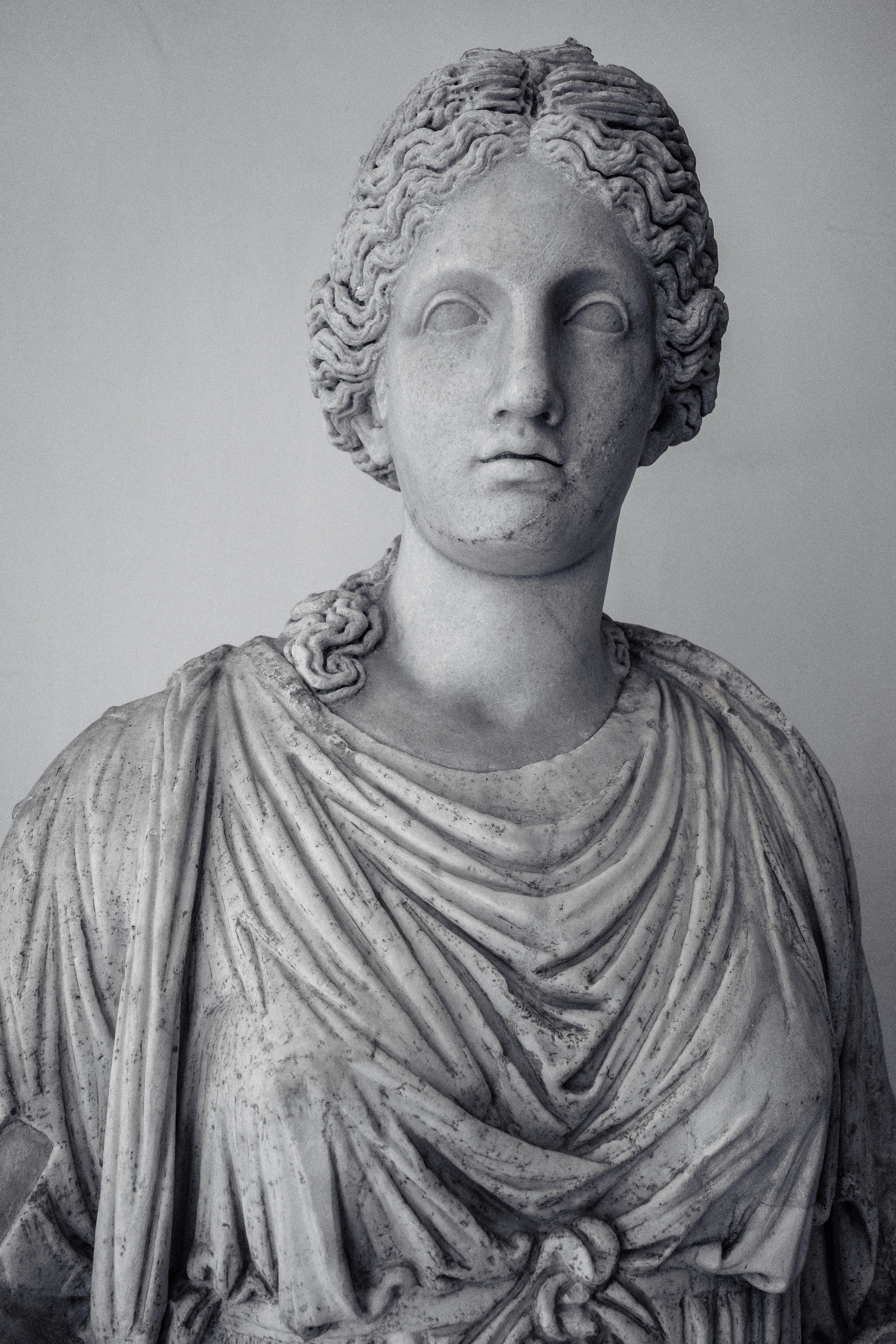 Classical marble statue of a woman draped in intricately detailed robes, exuding an aura of timeless elegance.