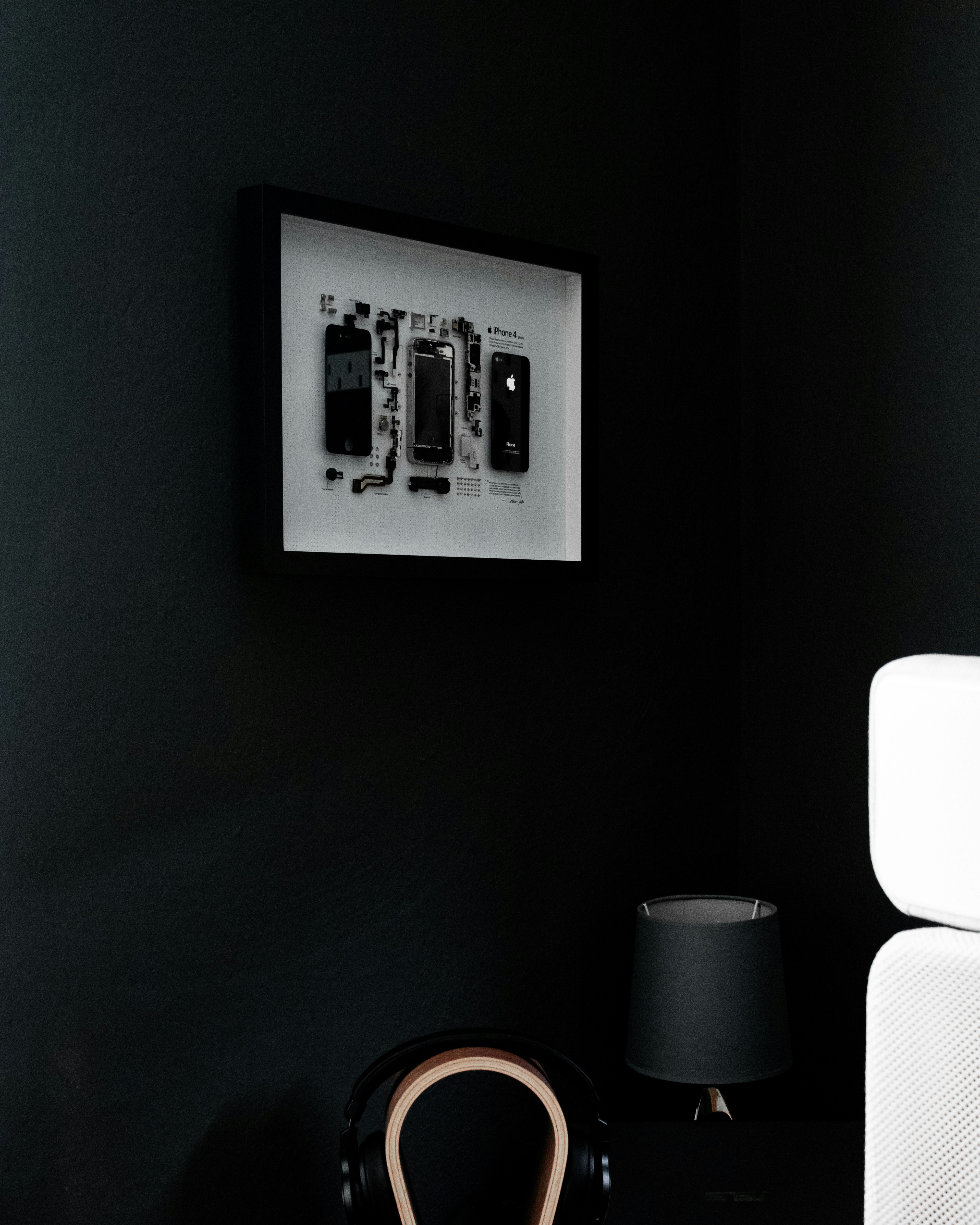 Artistic display of smartphone components framed against a dark wall, highlighting the intersection of design and technology.