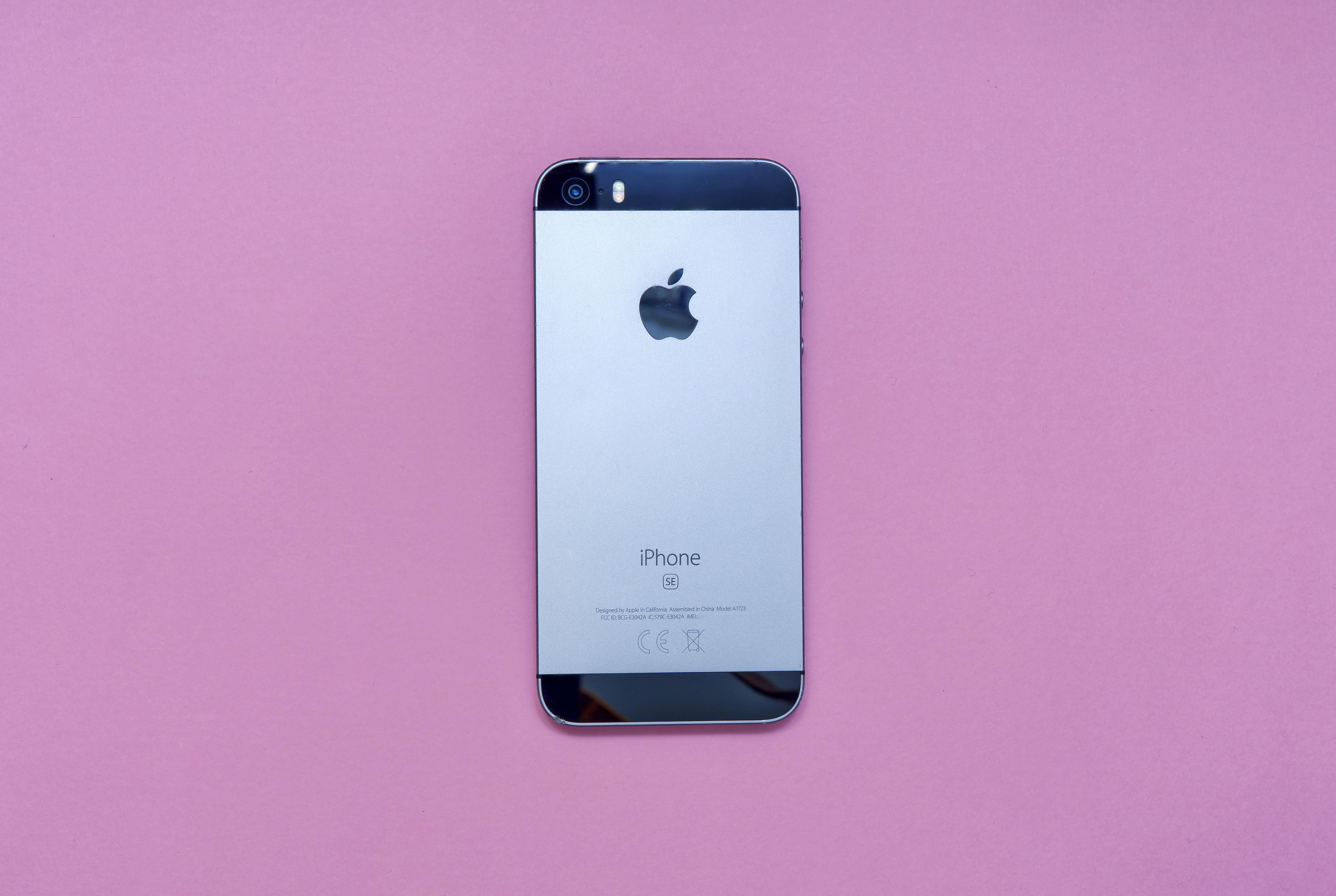 an iphone is sitting on a pink surface
