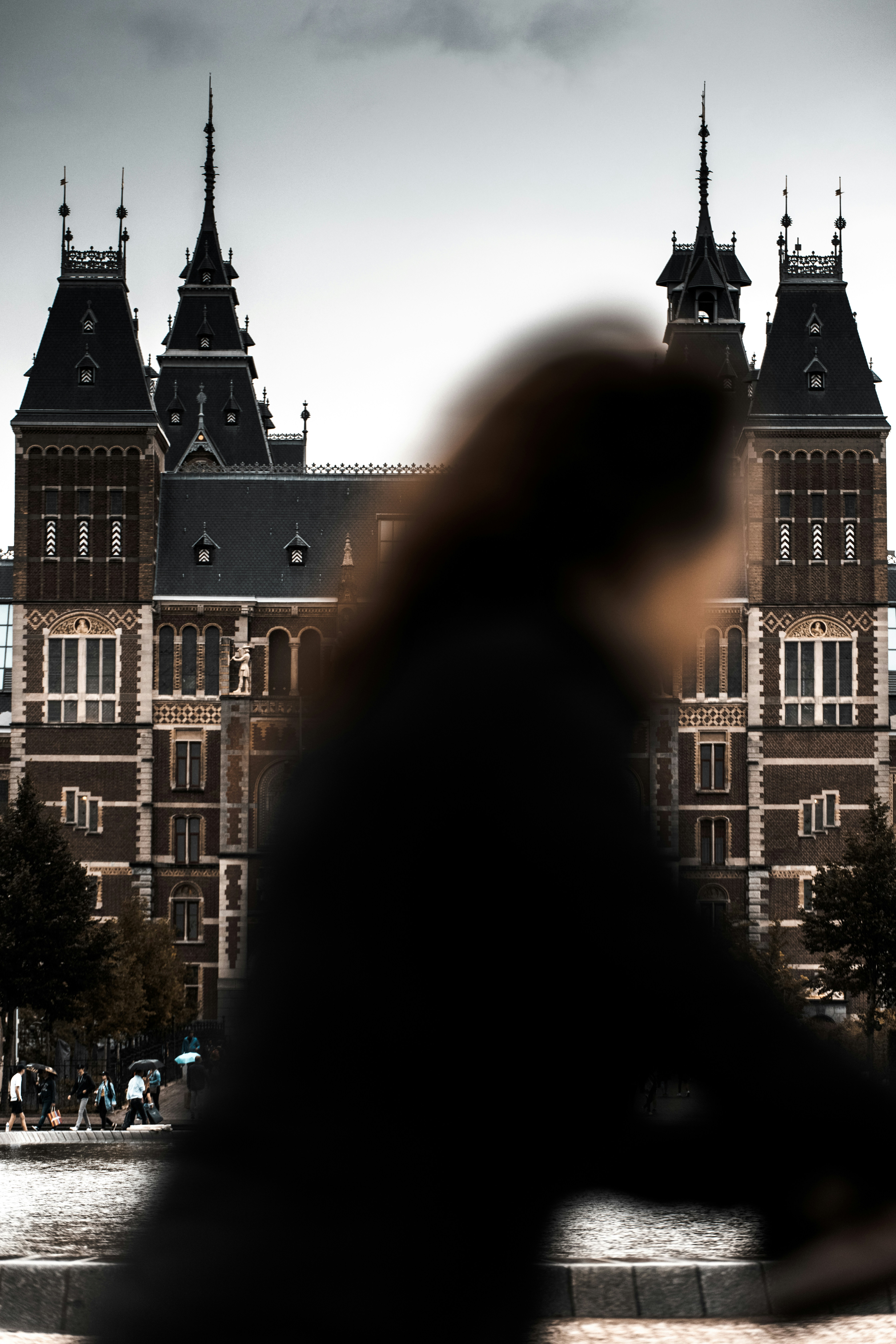Blurred foreground figure against the Rijksmuseum’s brick towers above Amsterdam’s canal