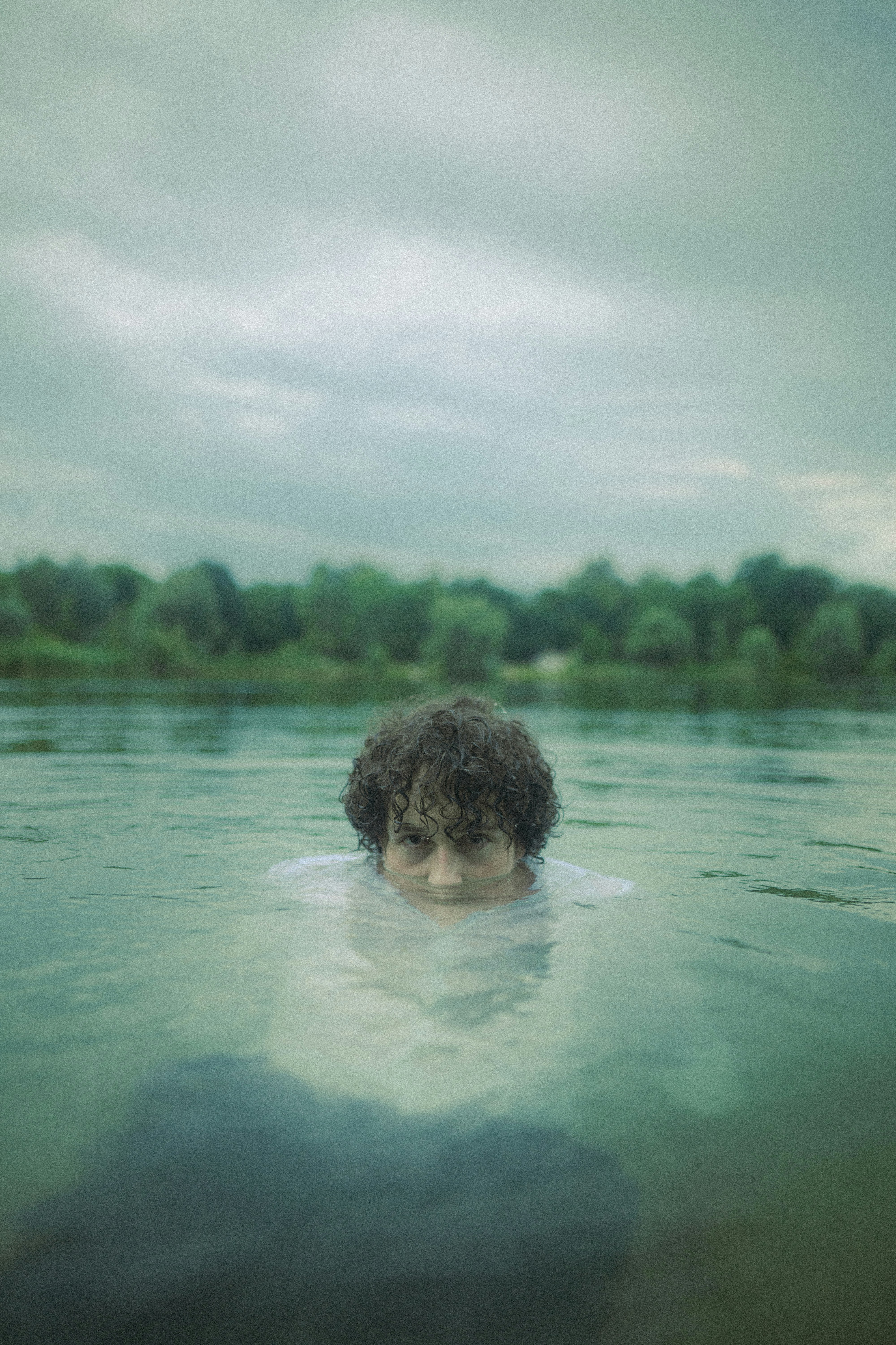 Green Lake Gaze: Curly Hair Emerging From Quiet Water