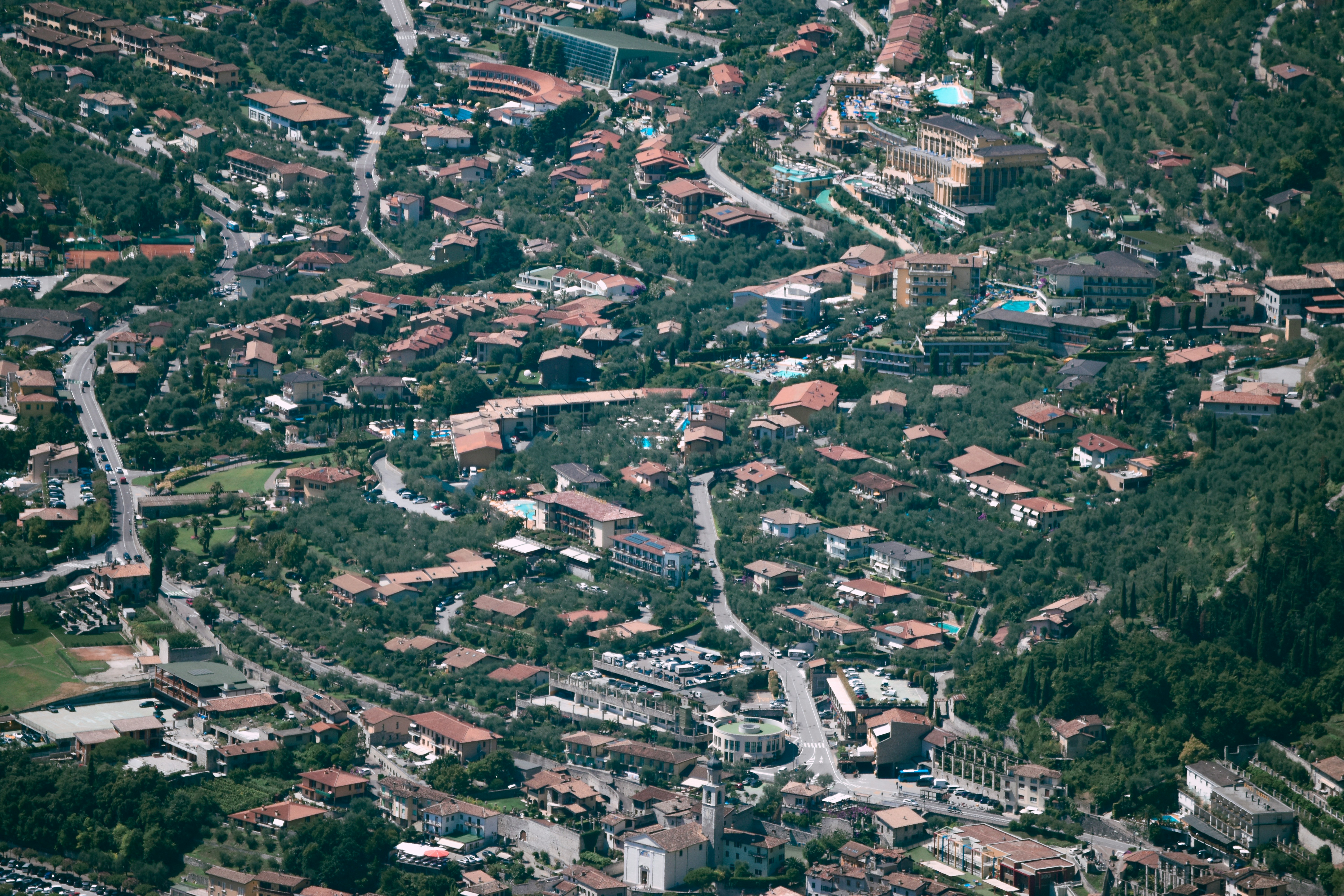 Aerial view showcasing a charming Italian village with terracotta rooftops nestled among lush greenery and winding roads.