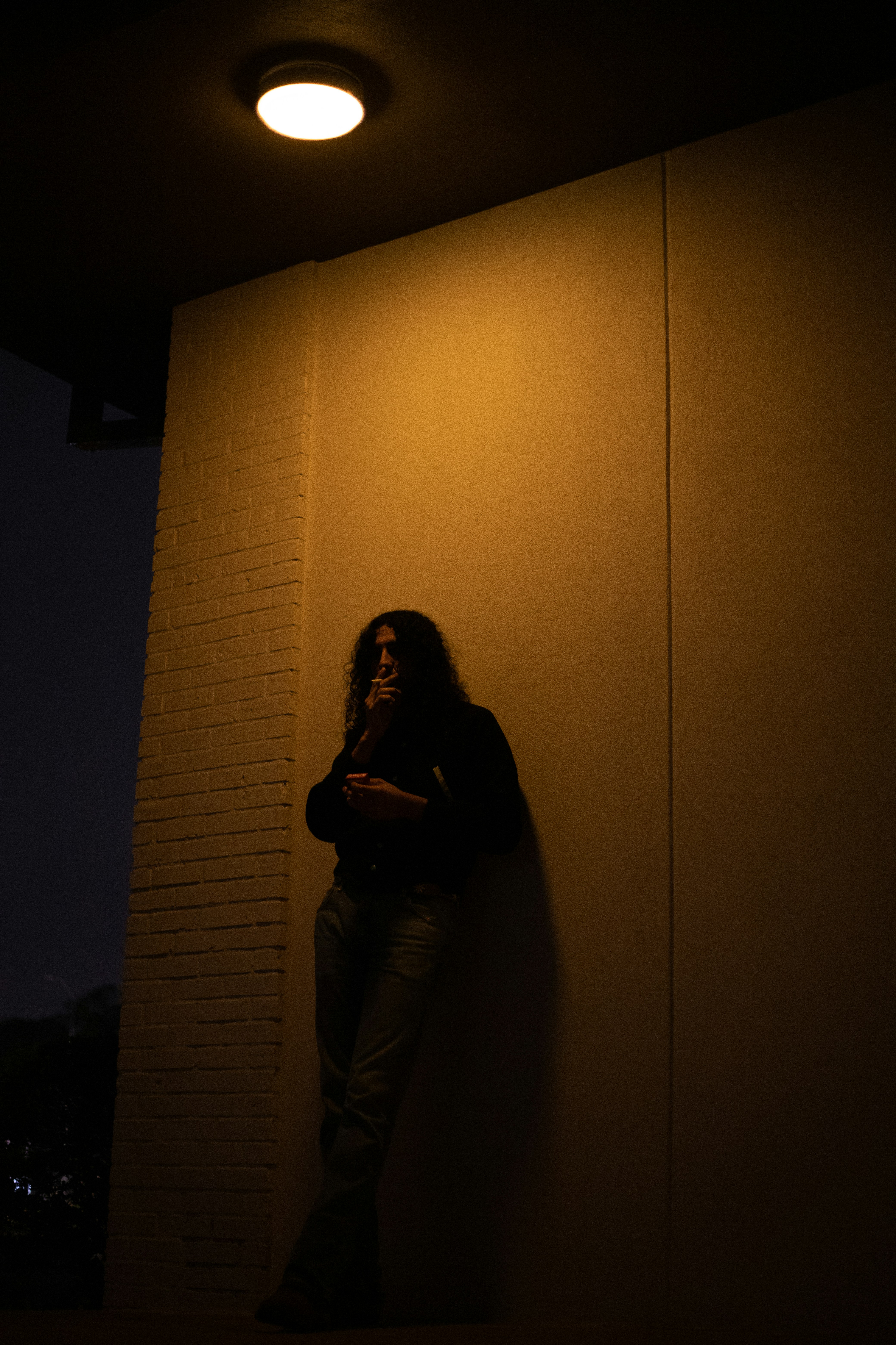Amber Halo at the Wall: A Quiet Figure in Night Light
