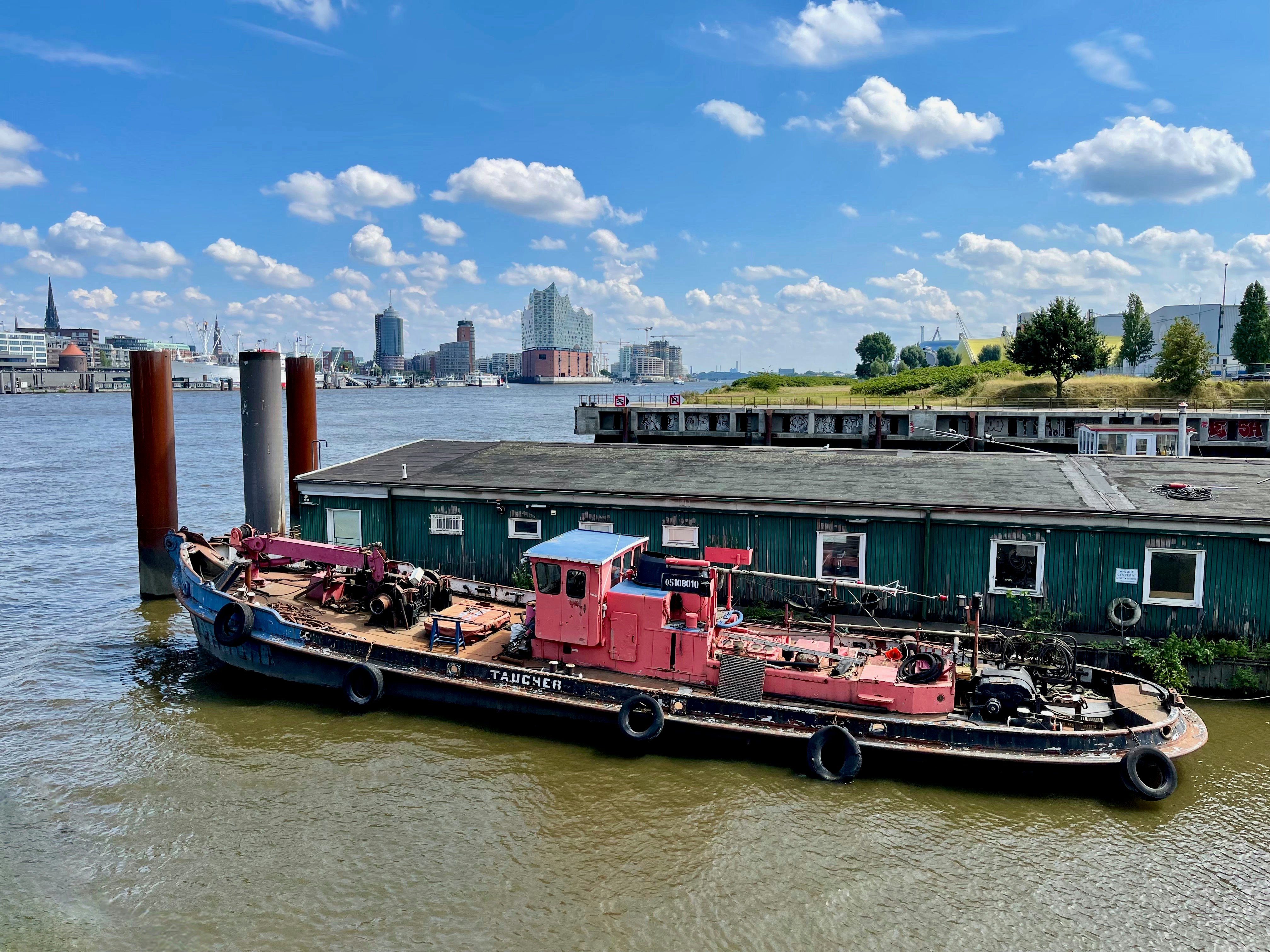 Rosy Tugboat at the Riverside: A Vessel Against a Modern City Skyline