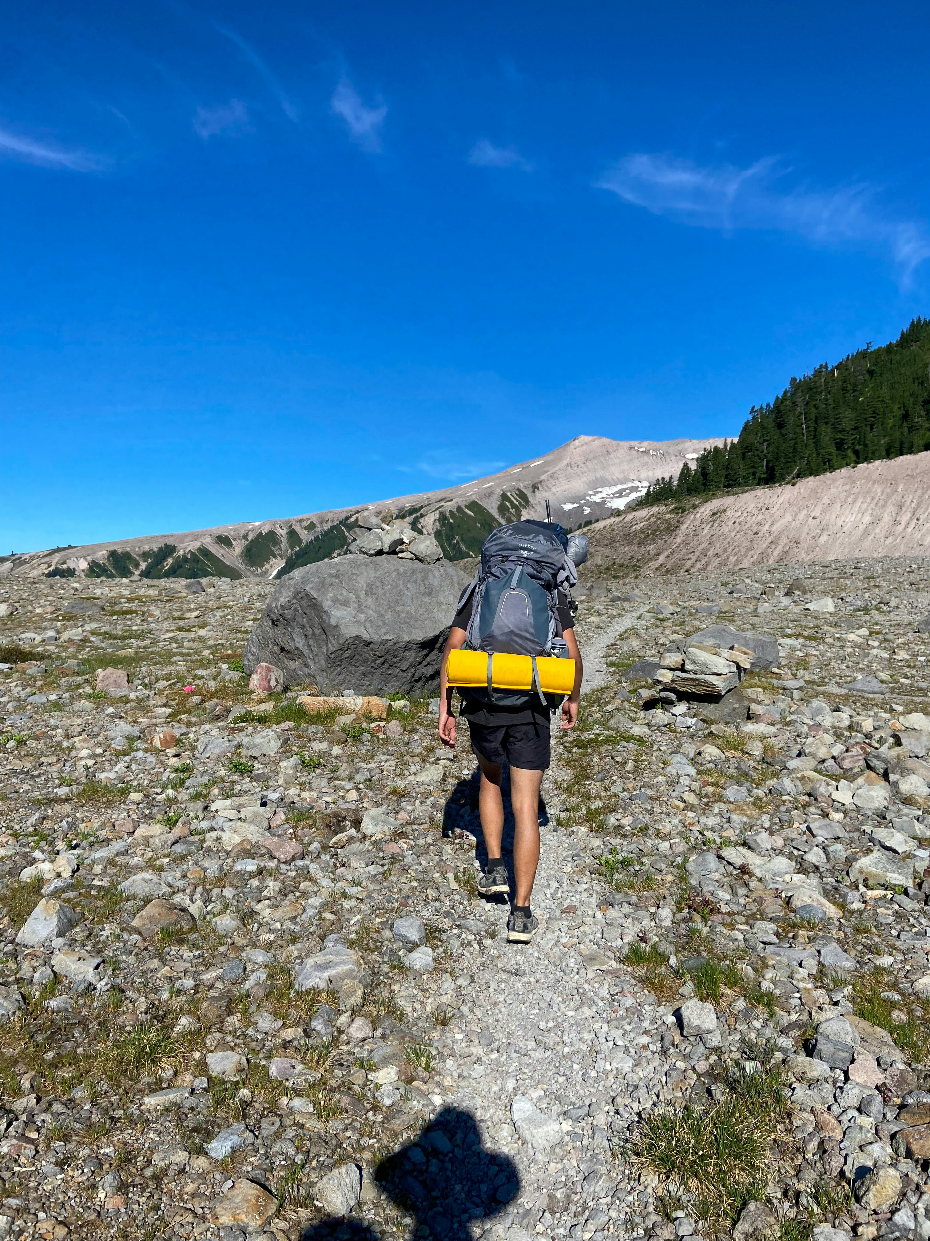 Trailbound: Climber with Yellow Rolled Maten Backpack Crossing a Rocky Alpine Plain